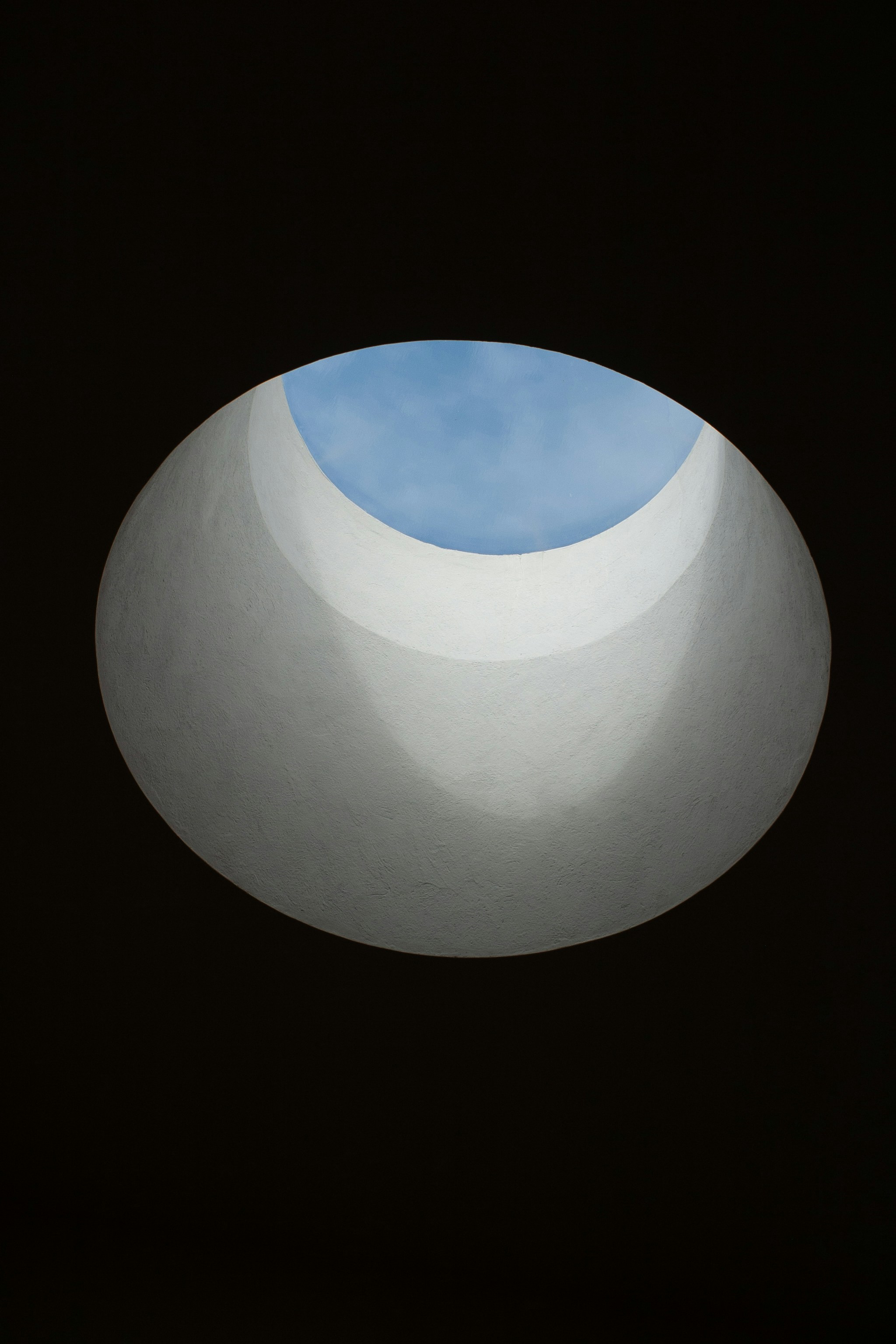 Circular white opening frames blue sky within a dark surround.
