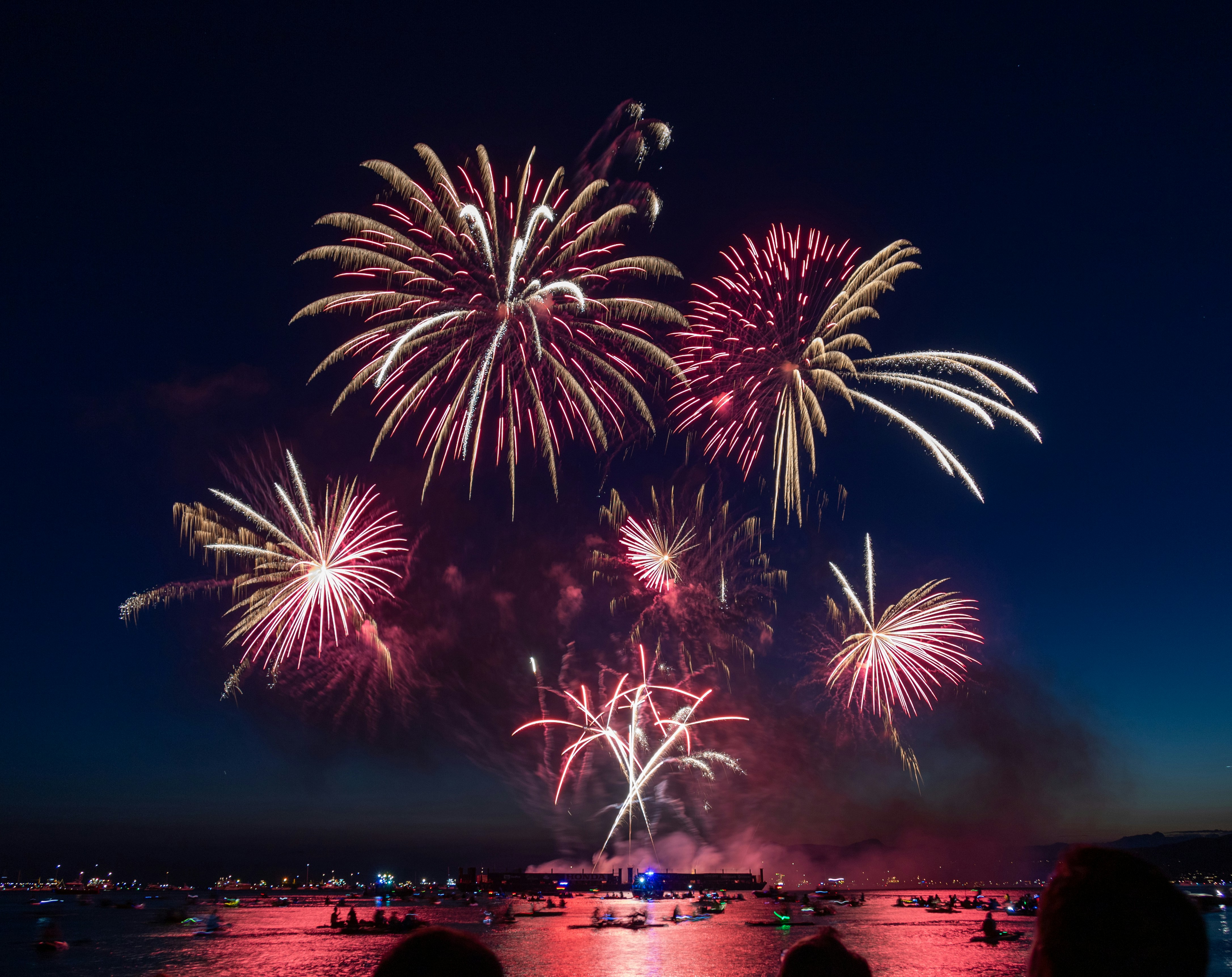 A group of people watching fireworks on the water photo – Free ...