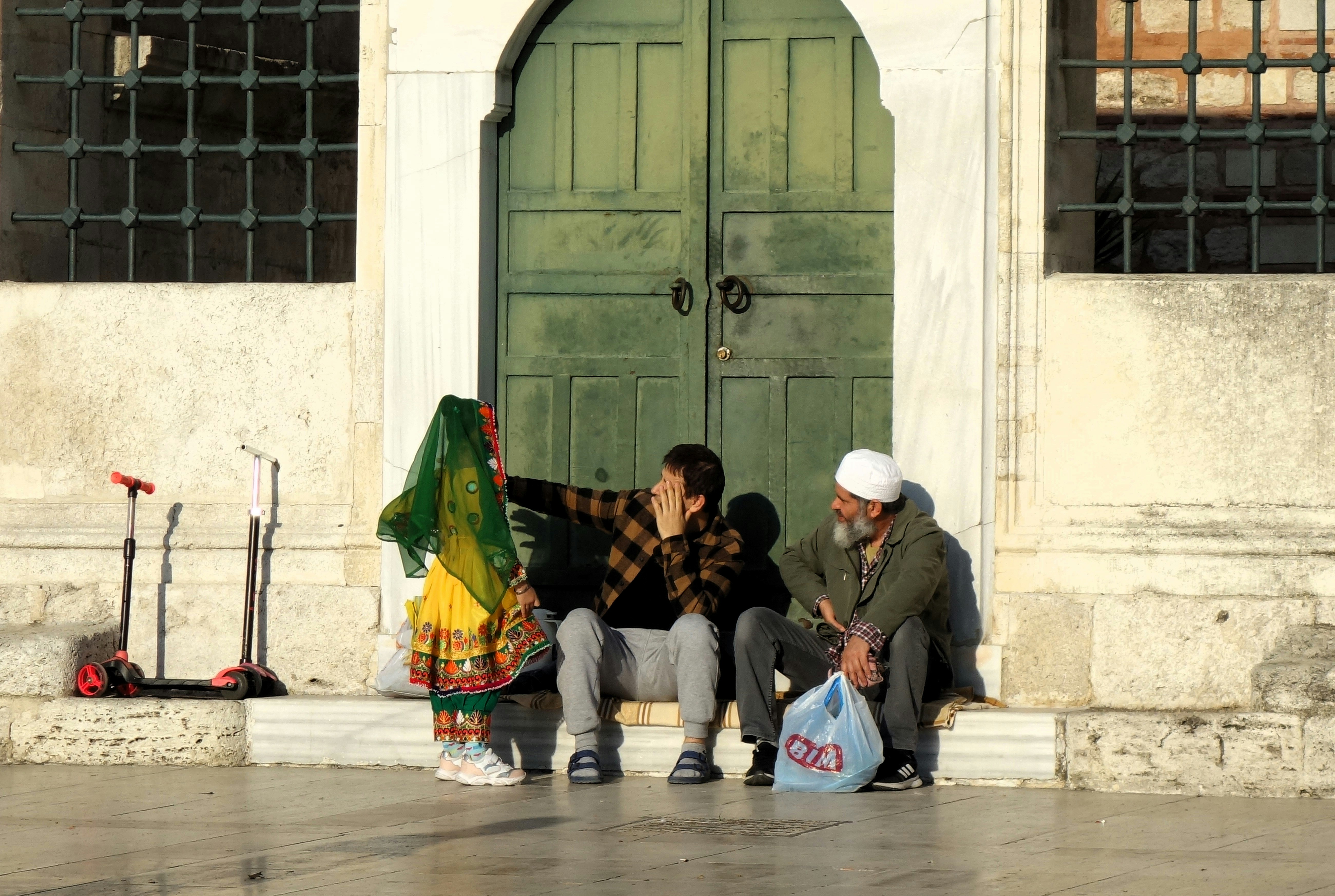 Three Companions by a Weathered Green Door: Quiet Pause on the Steps
