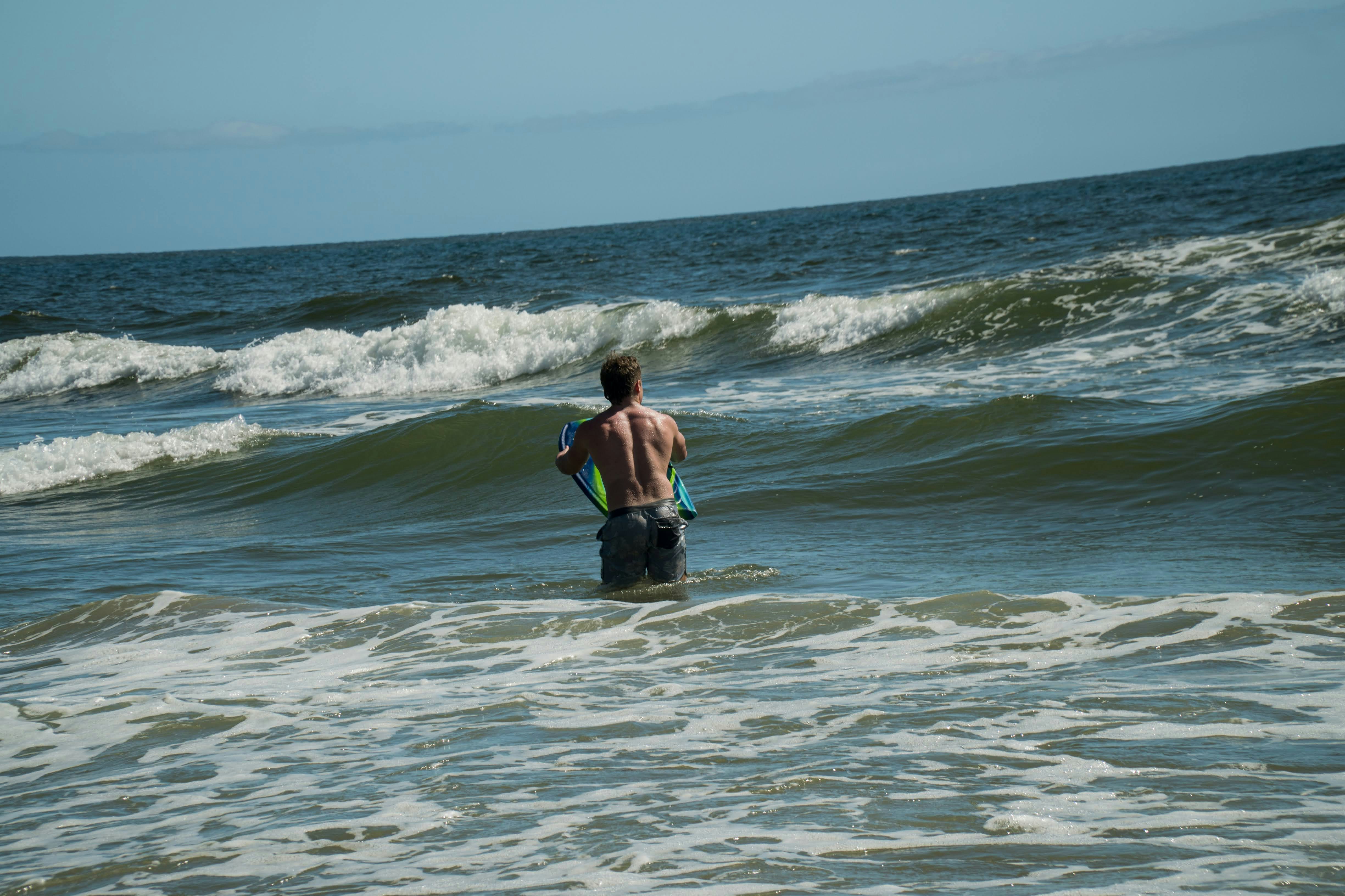Silhouetted Surfer Stands Waist-Deep, Meeting the Atlantic Break