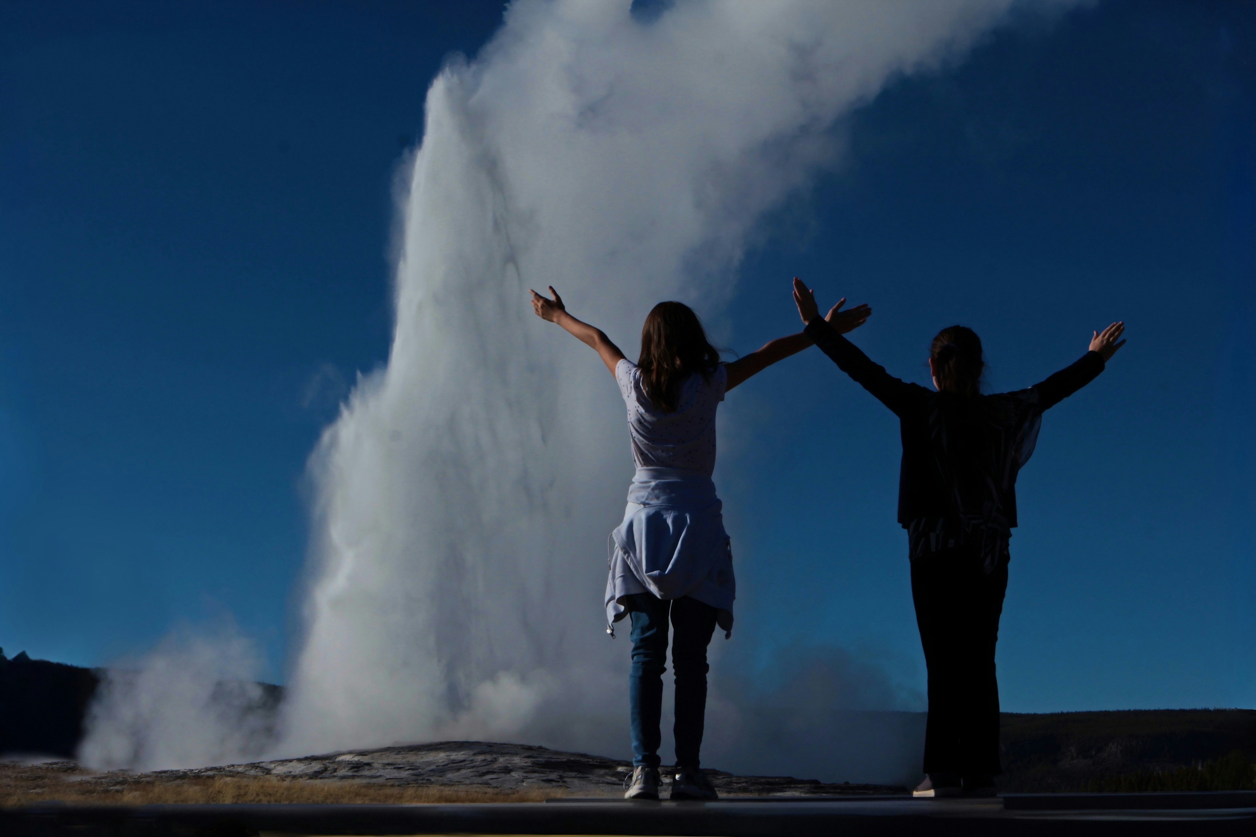 Arms Up, Steam Up: Silhouettes Before a Geyser's Eruption