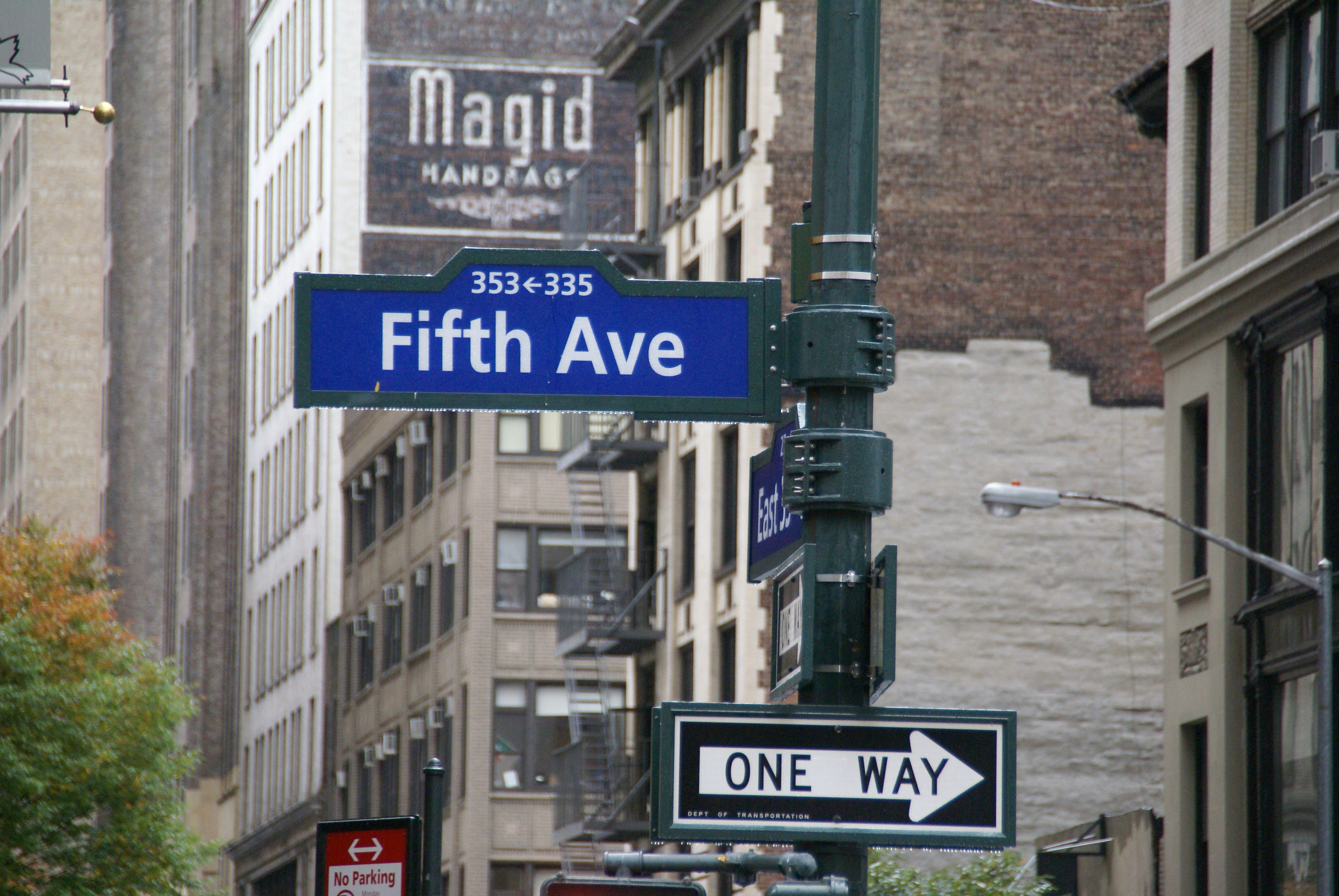 Fifth Avenue street sign prominently displayed amidst a bustling cityscape, with vintage advertisements in the background. The scene captures the essence of urban life.