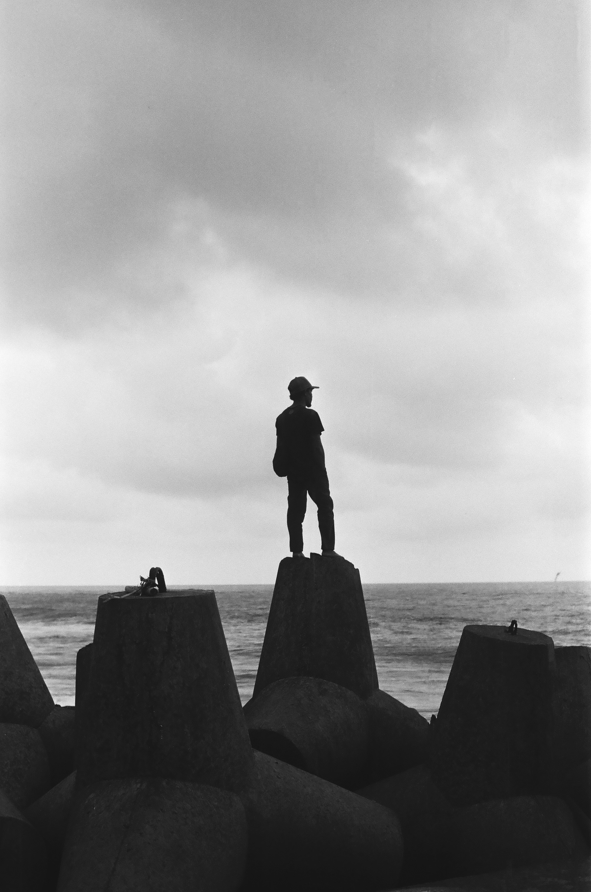 A black and white photo of a man standing on rocks photo – Free Film ...
