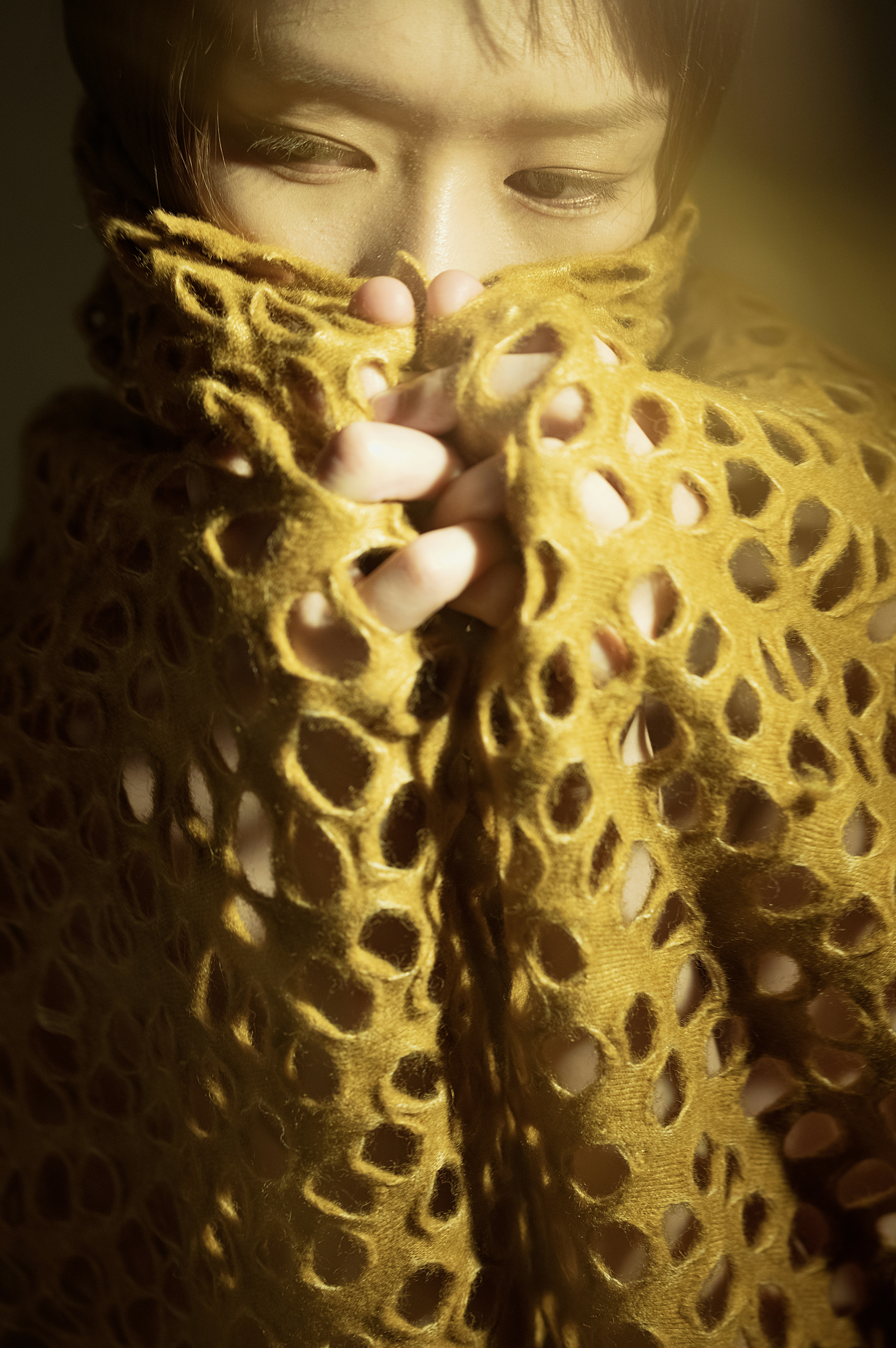 Amber Lattice Moment: Hands Teasing Light Through a Knit Veil