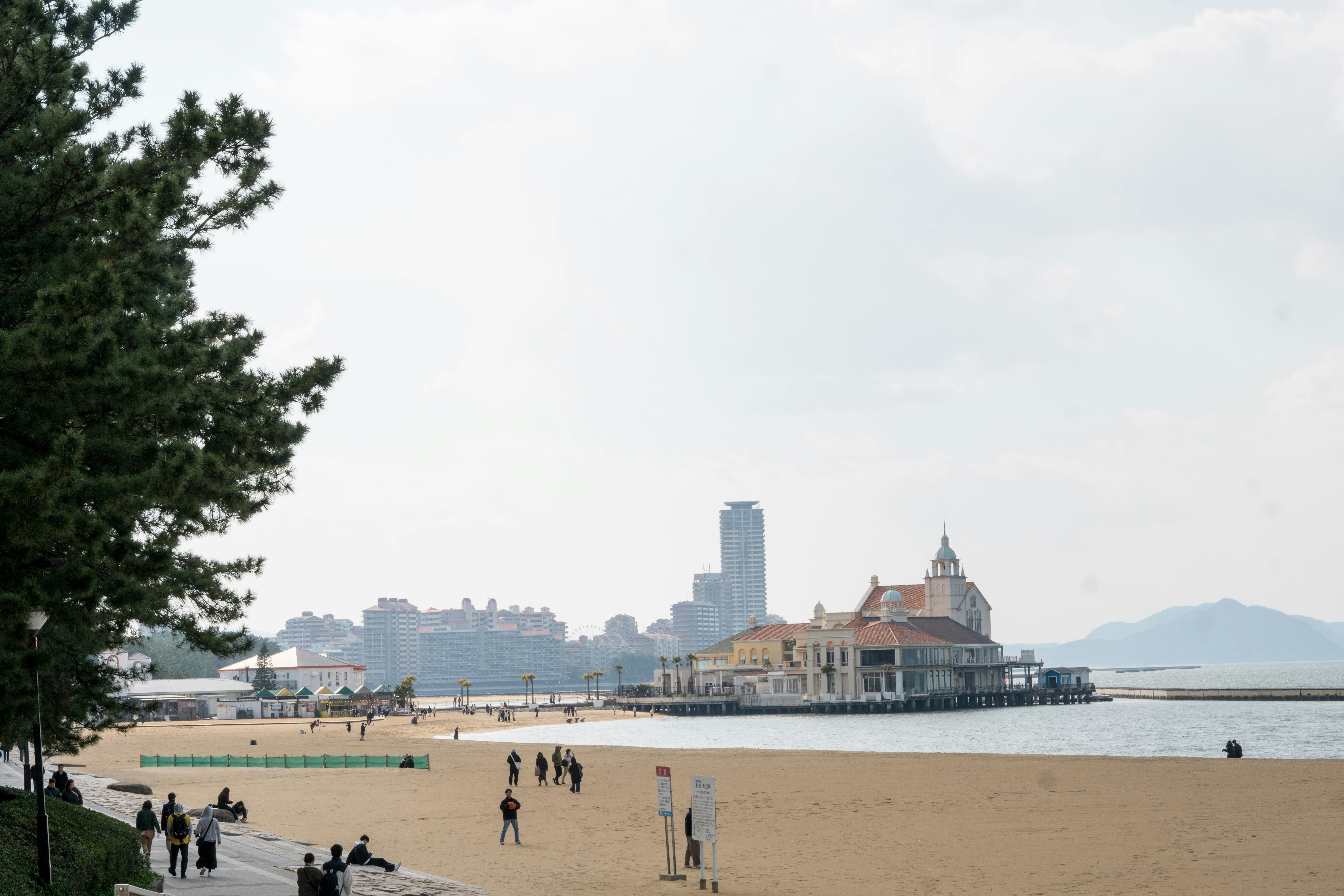 Pierfront Pavilion Over Quiet Harbor: Beach, Pier, and Distant Skyline