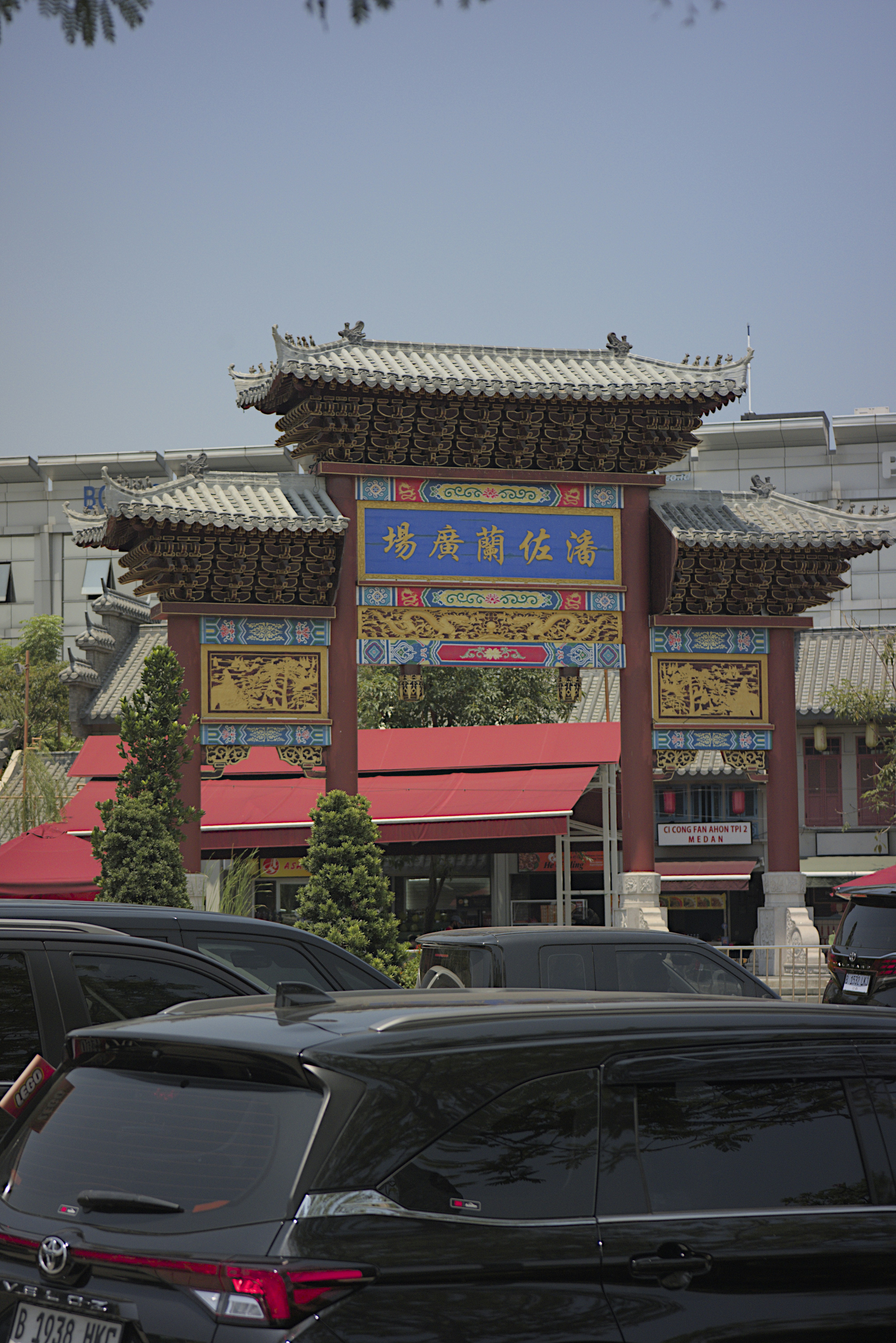 Dragon-Topped Paifang Over a Car-Laden Street