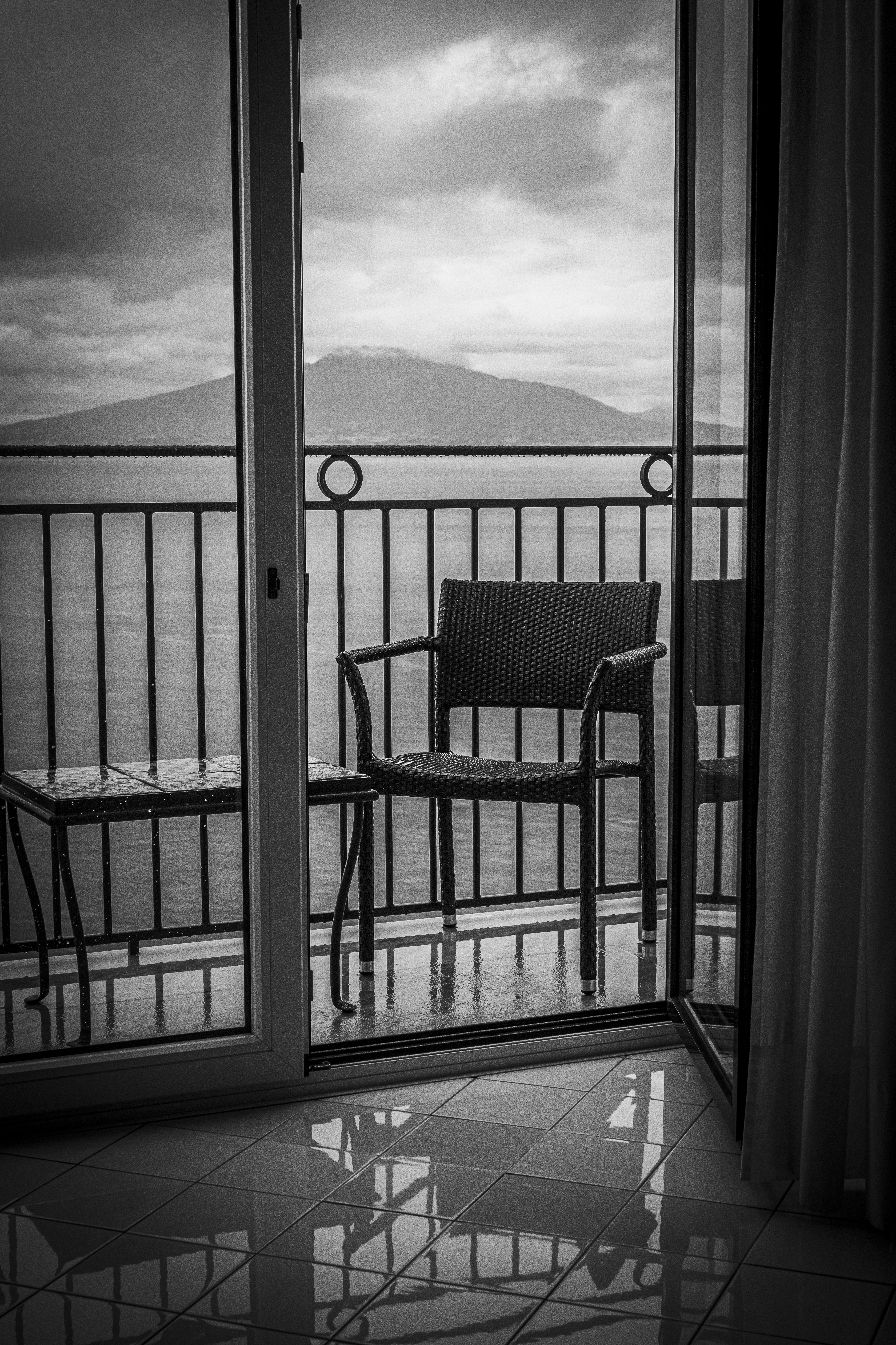 Balcony Vista: Empty Chair, Quiet Sea, and Windows to a Distant Island