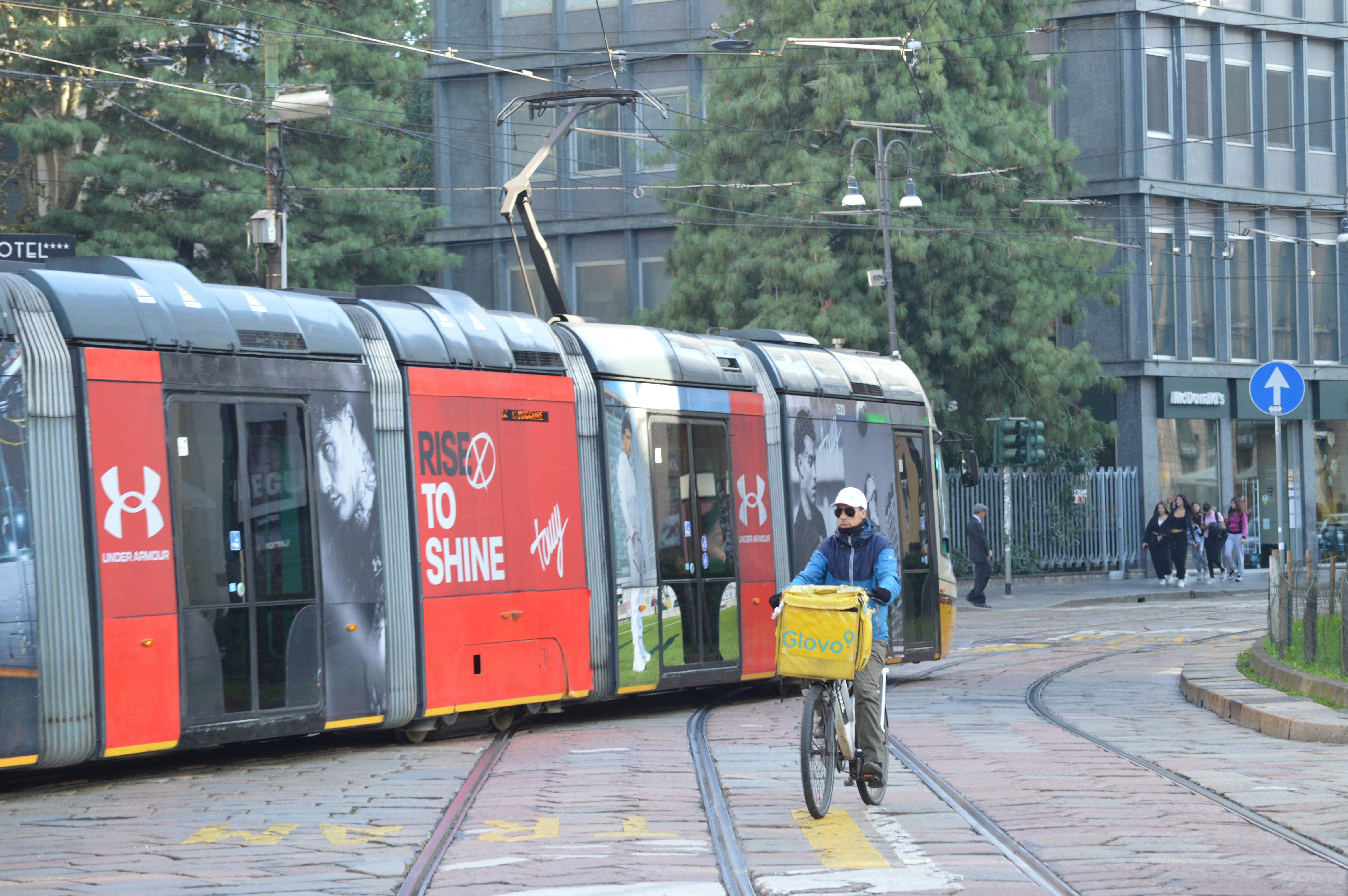 Courier on Rails: A Cyclist with a Yellow Pannier Beside a Red City Tram