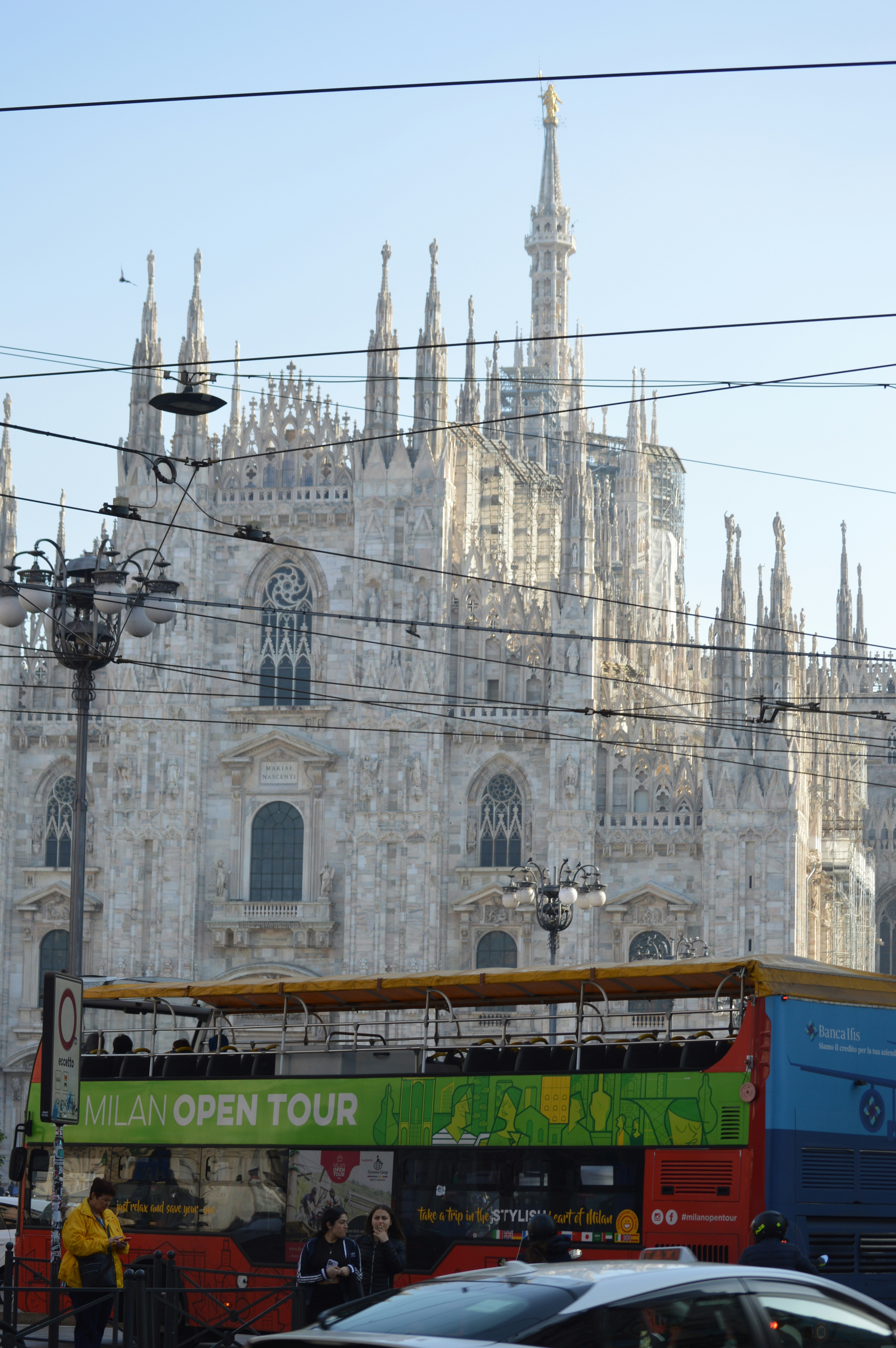 Gothic marble and open-top tour bus under Milan’s cathedral spires