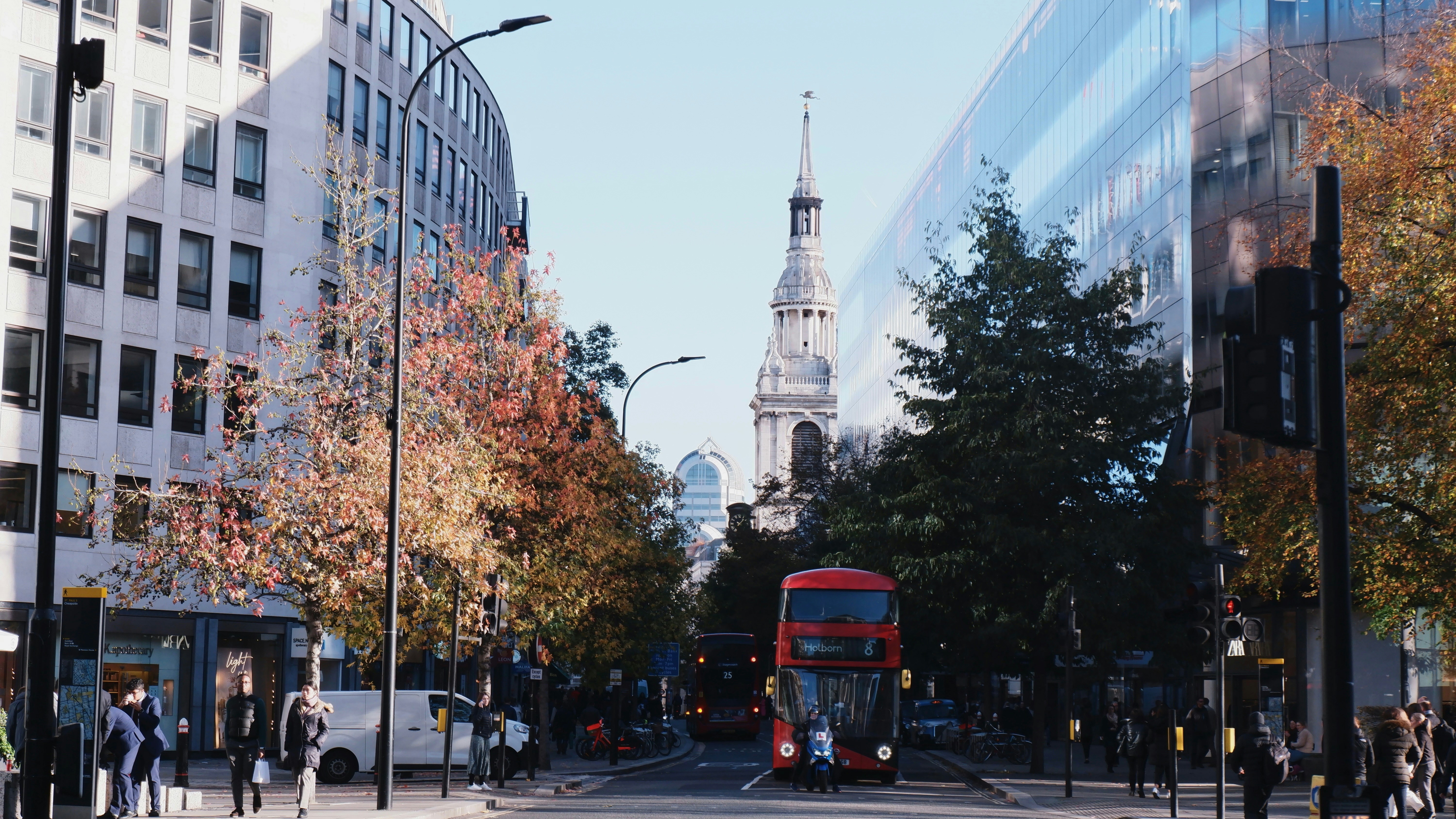 Crimson Double-Decker Framed by Glass Giants and a Spire
