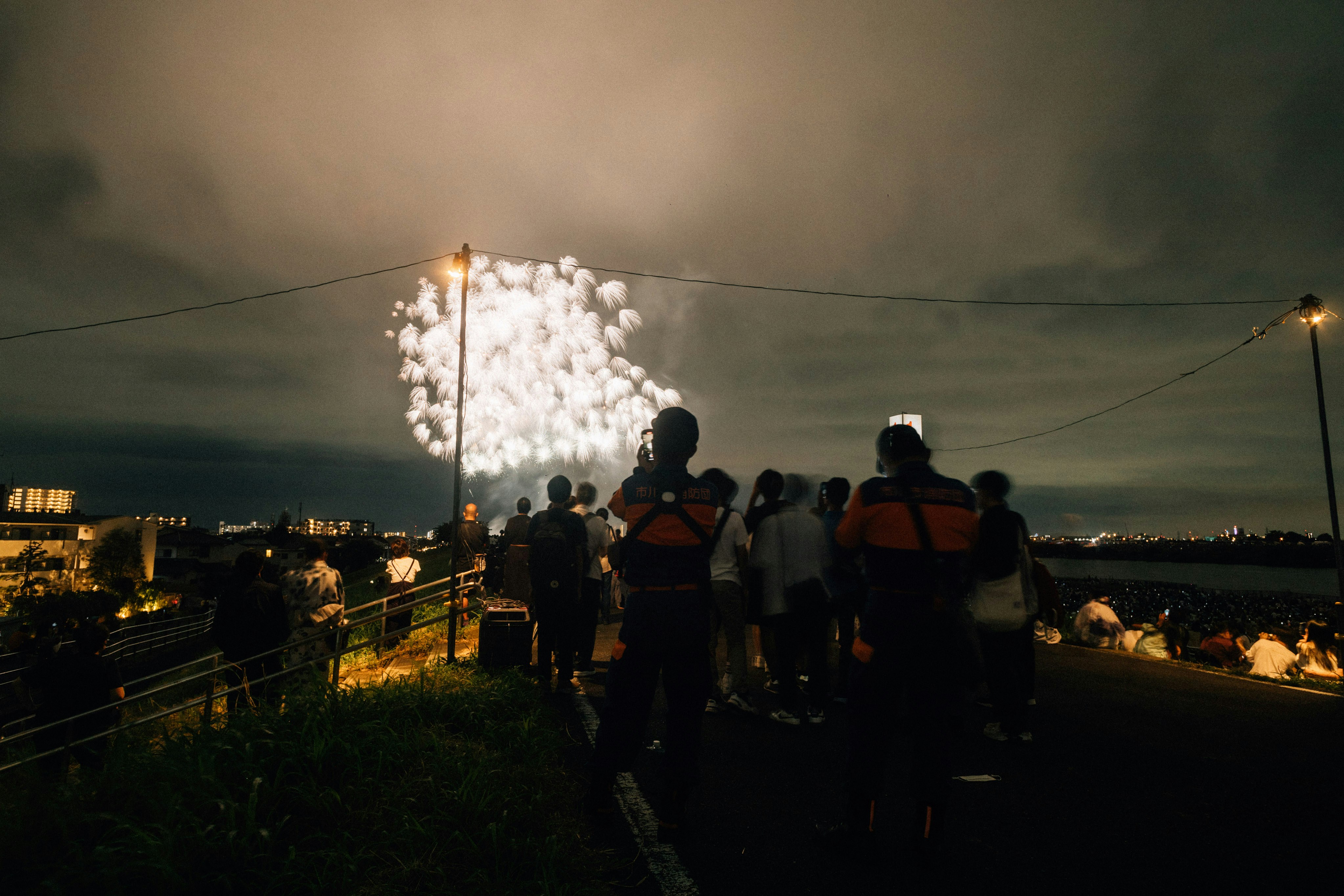 A group of people watching fireworks go off in the sky photo – Free ...