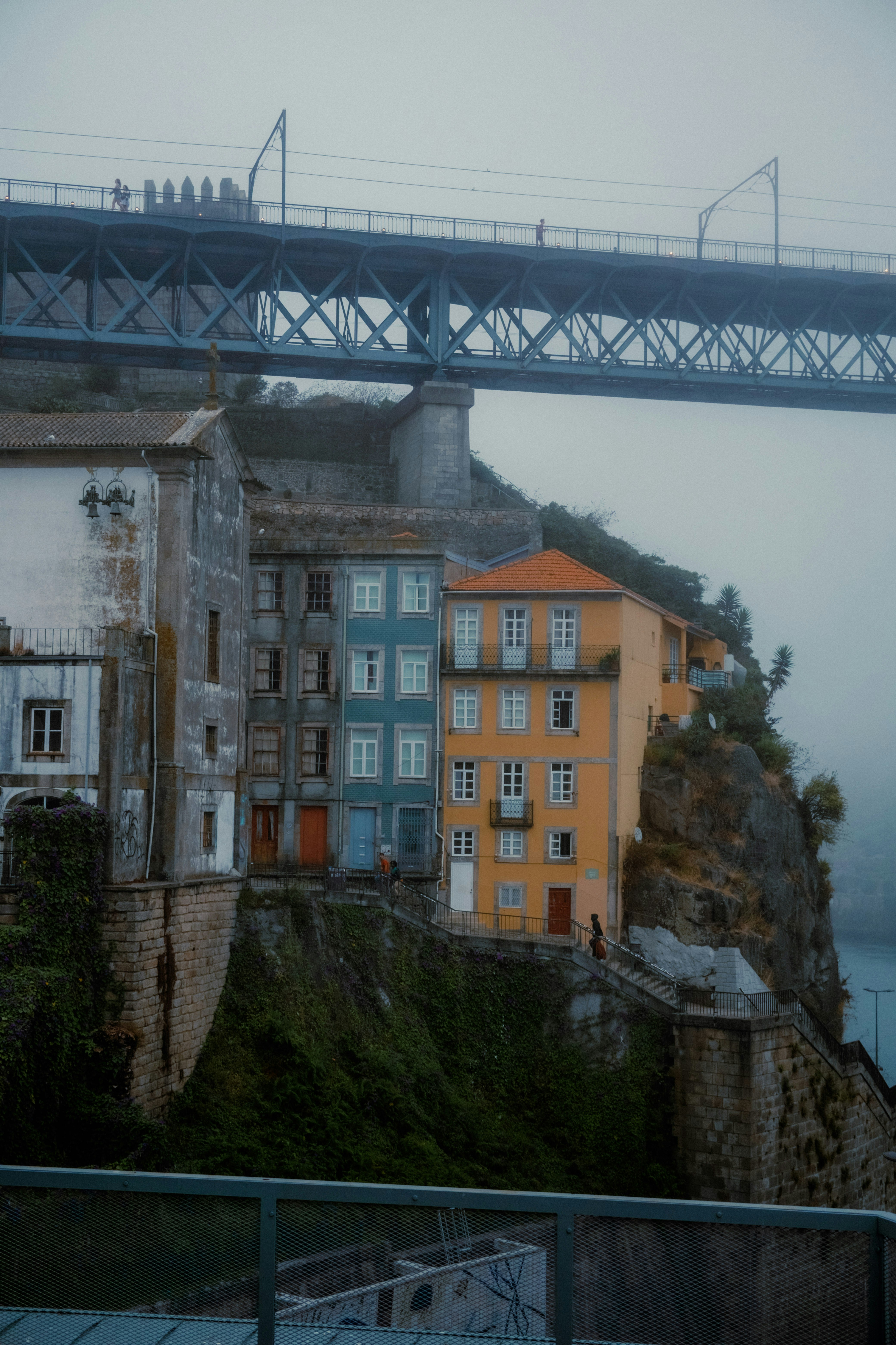 Colorful cliffside houses beneath a steel bridge