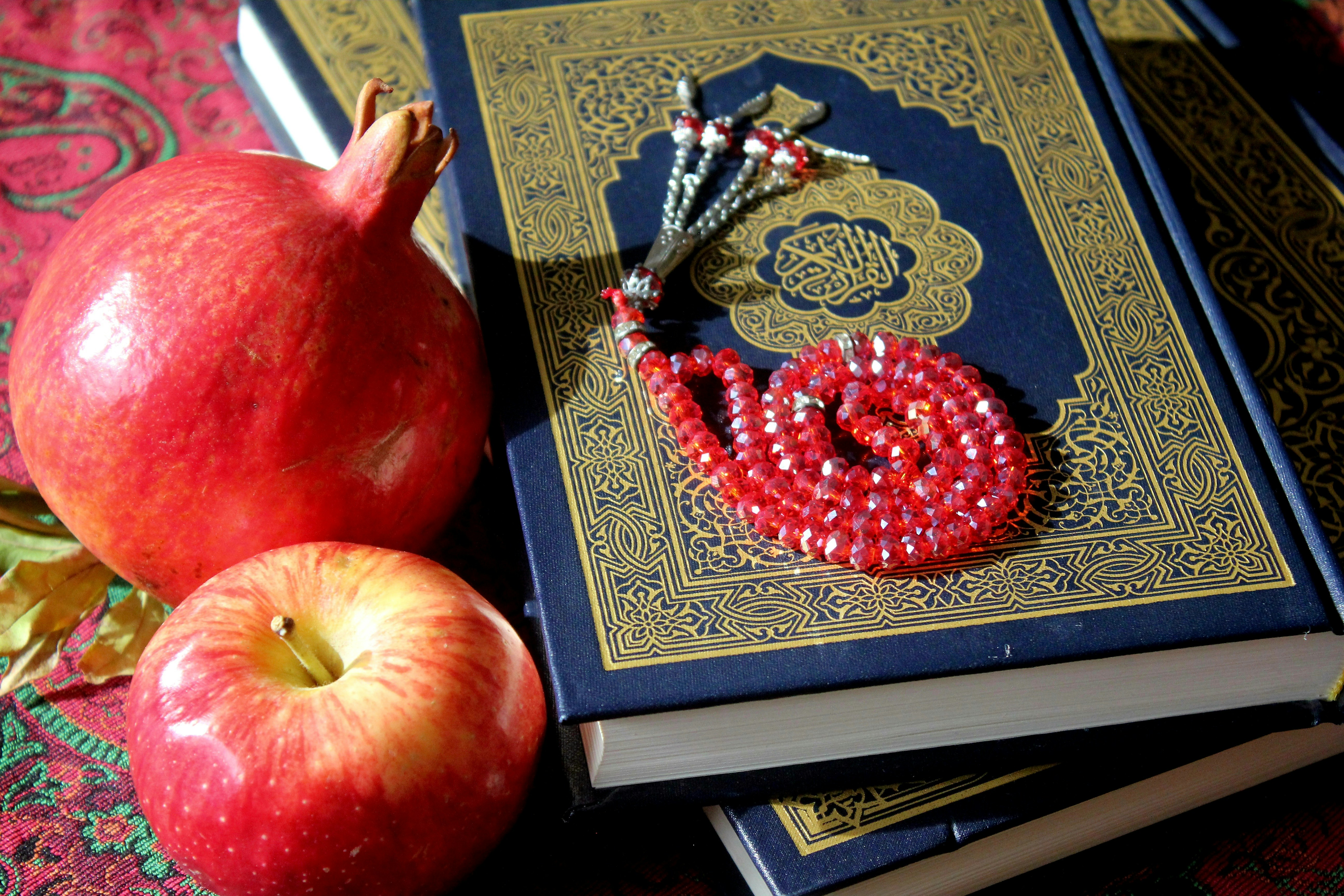 Crimson Rosary Draped Across a Blue-Gold Tome Beside Apples