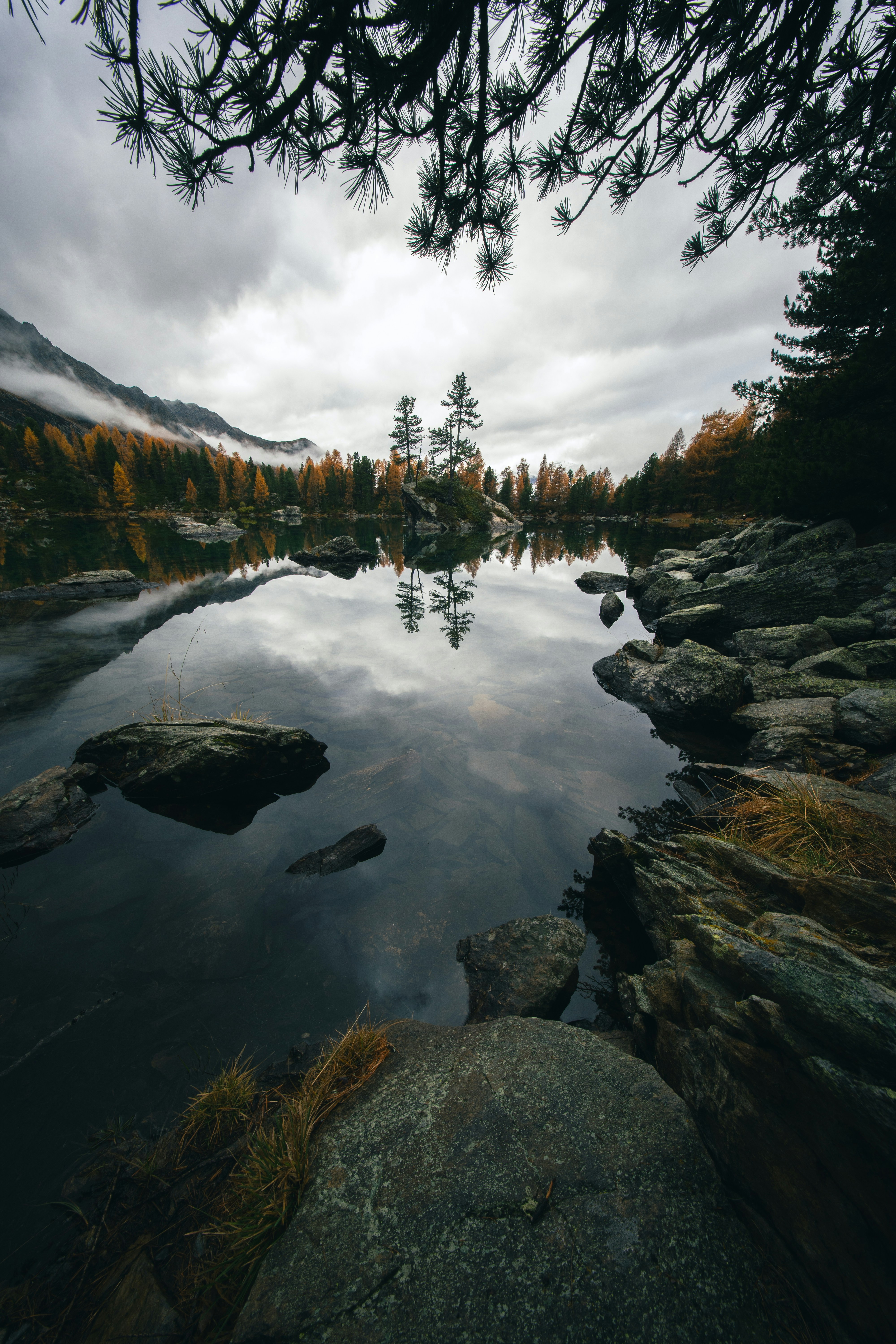 A body of water surrounded by rocks and trees photo – Free Nature Image ...