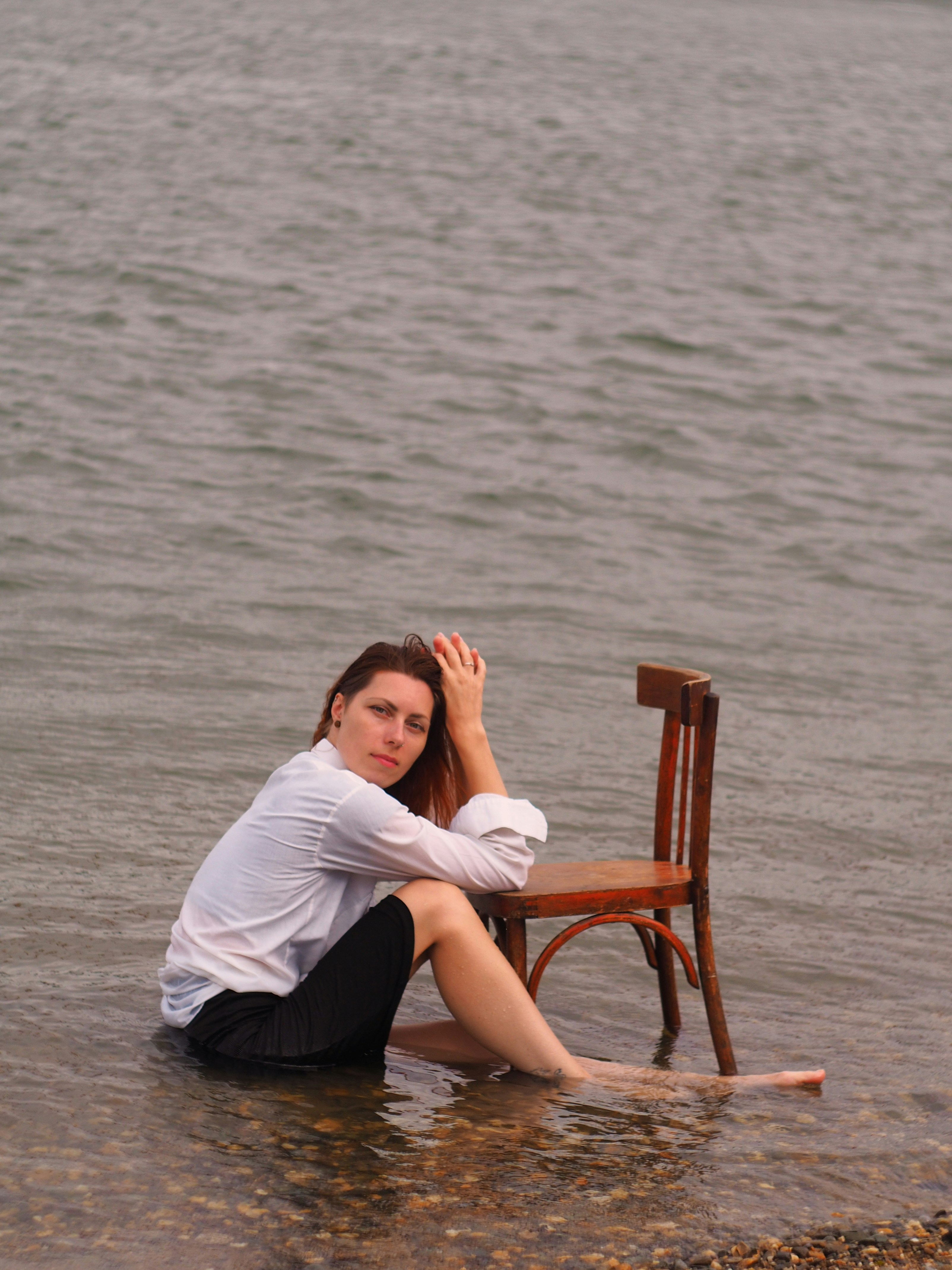 Edge of Quiet: A Woman and a Wooden Chair Rest at the Shore