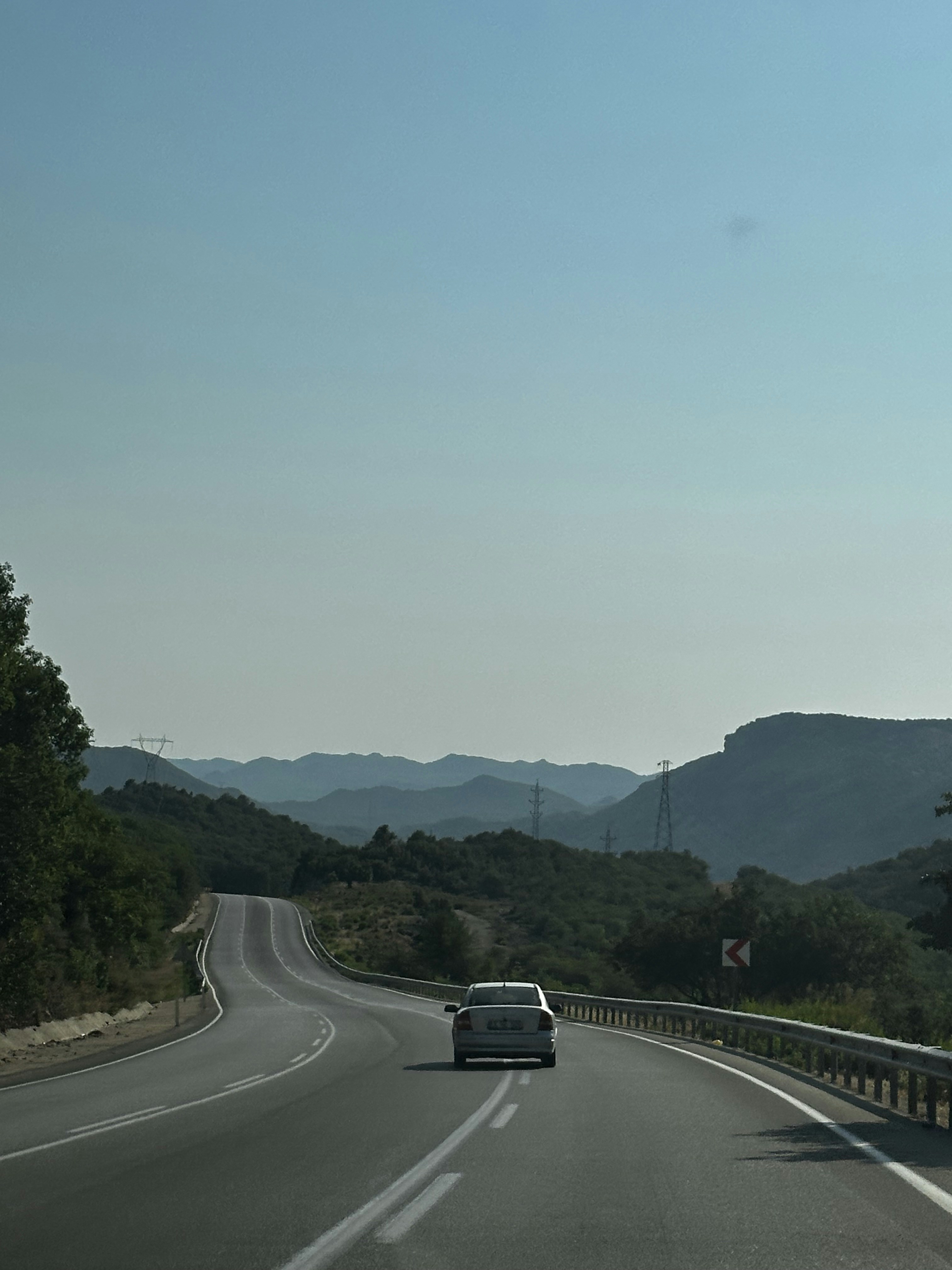 Silver Sedan on a Serpentine Mountain Road Under a Clear Blue Sky