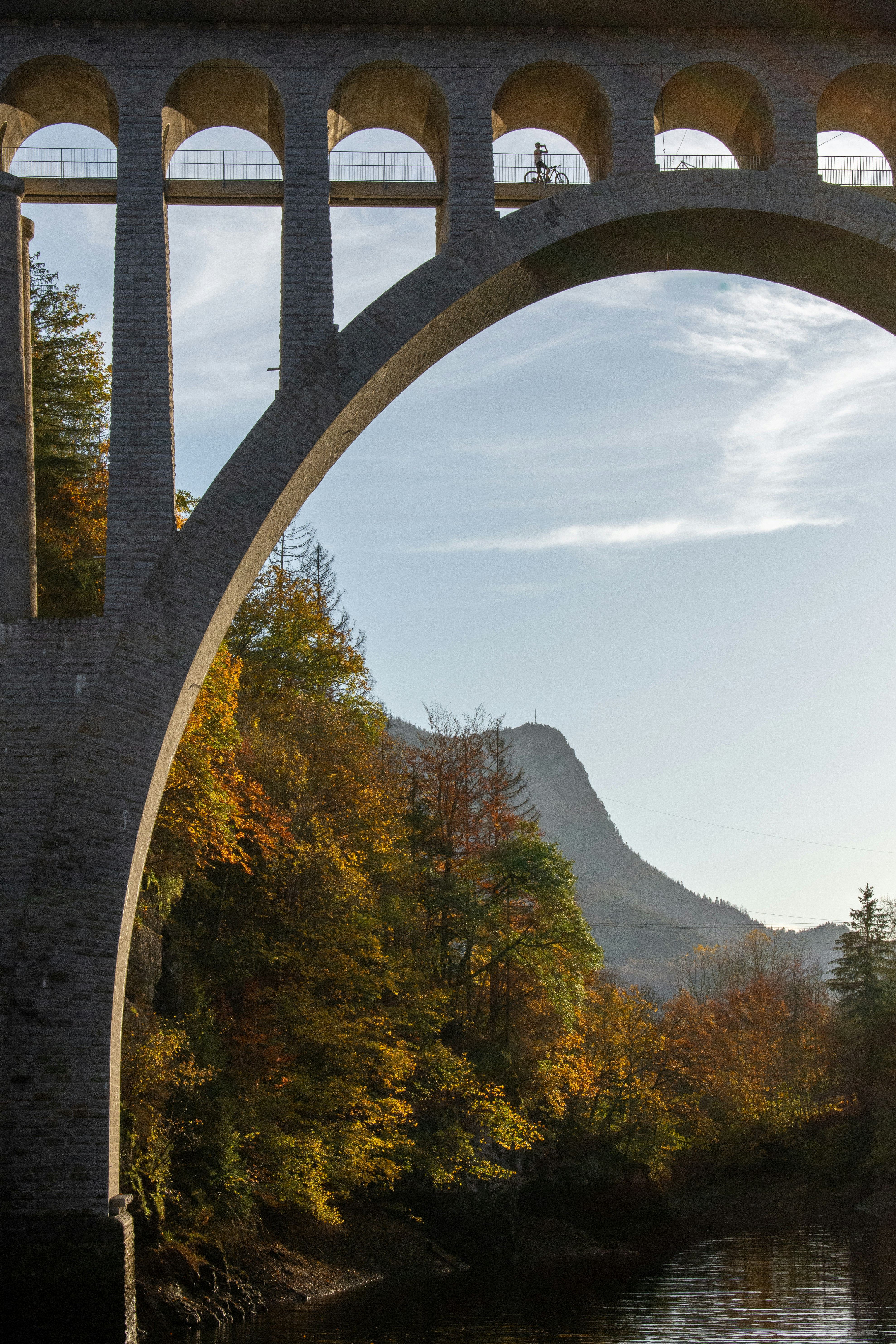 Rider on the Crown of a Stone-Arch Viaduct Amid Autumn Light