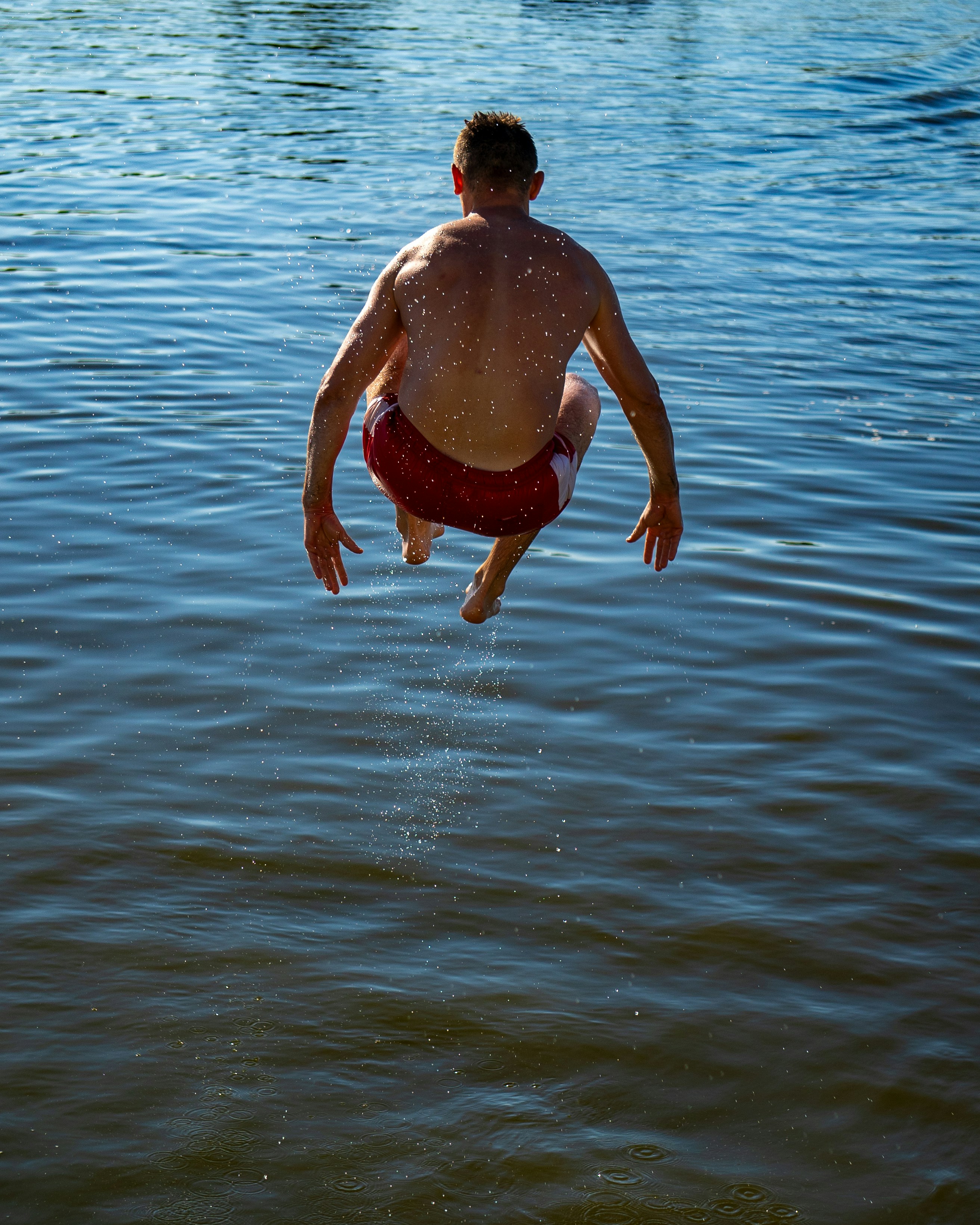 Back-View Leap into a Sunlit Blue Lake