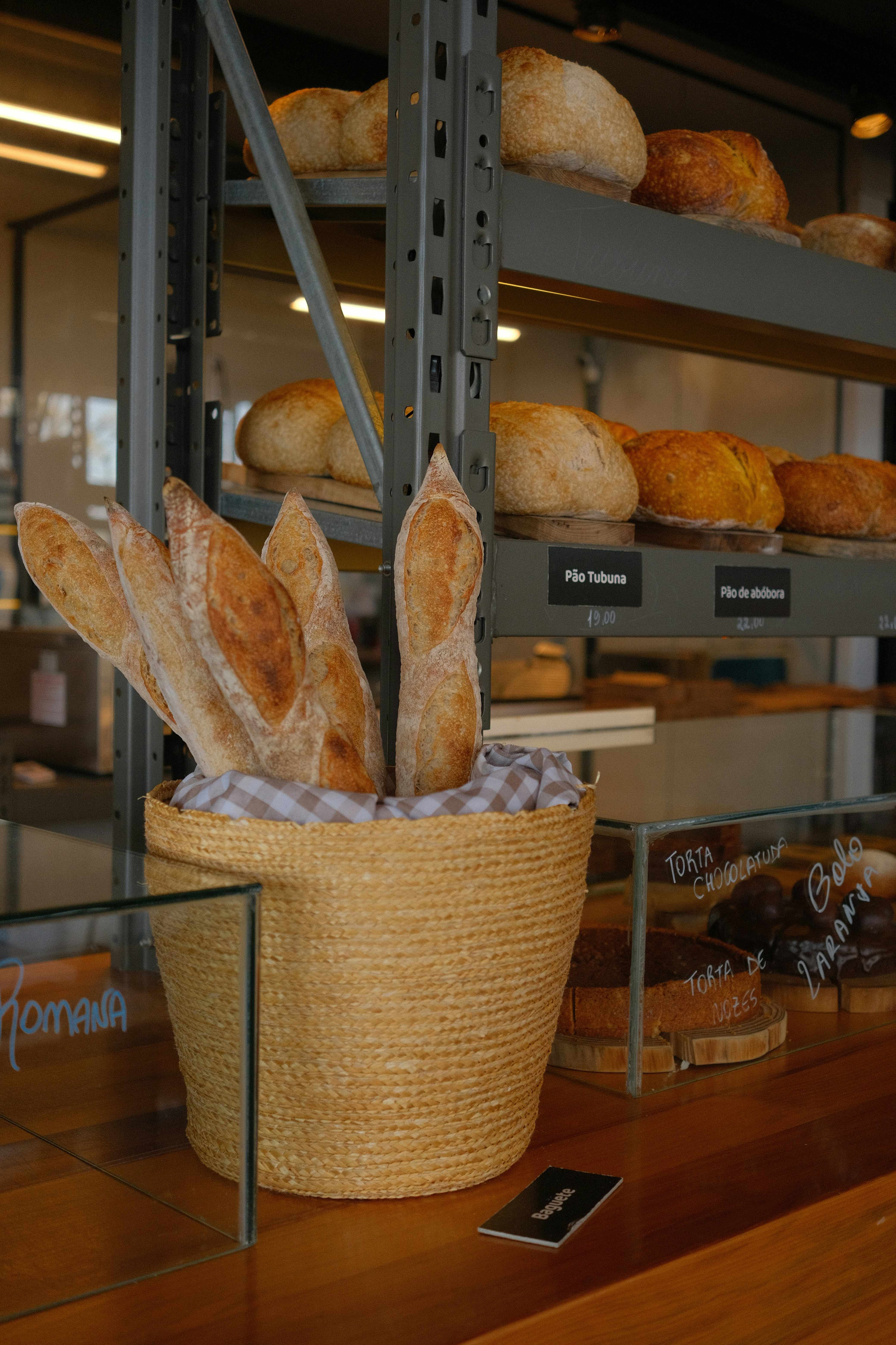 Crust in Focus: Baguettes Rising in a Basket Before a Wall of Loaves