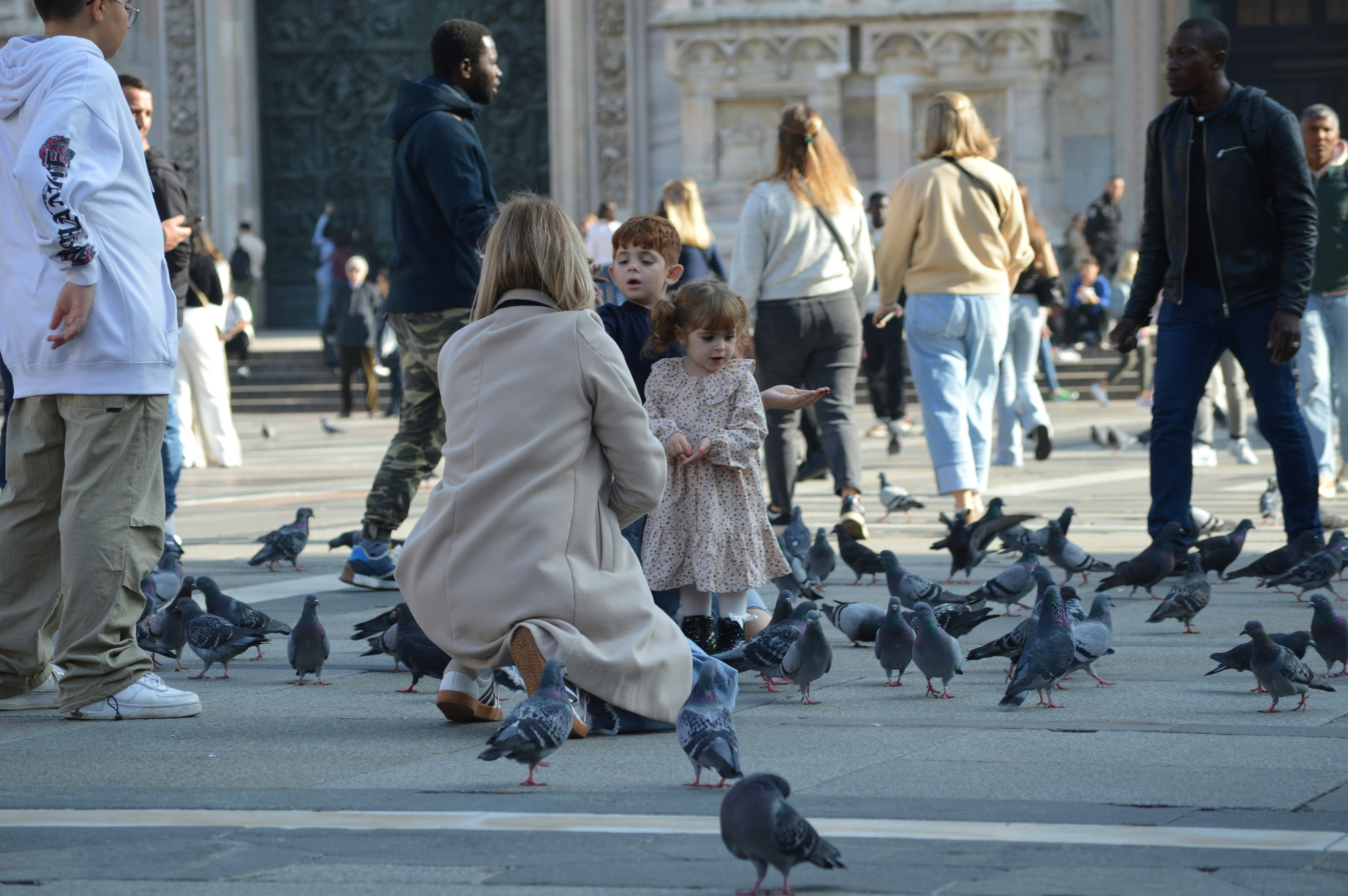 Soft Moment in a City Square: Children and Doves Amidst Shy Onlookers