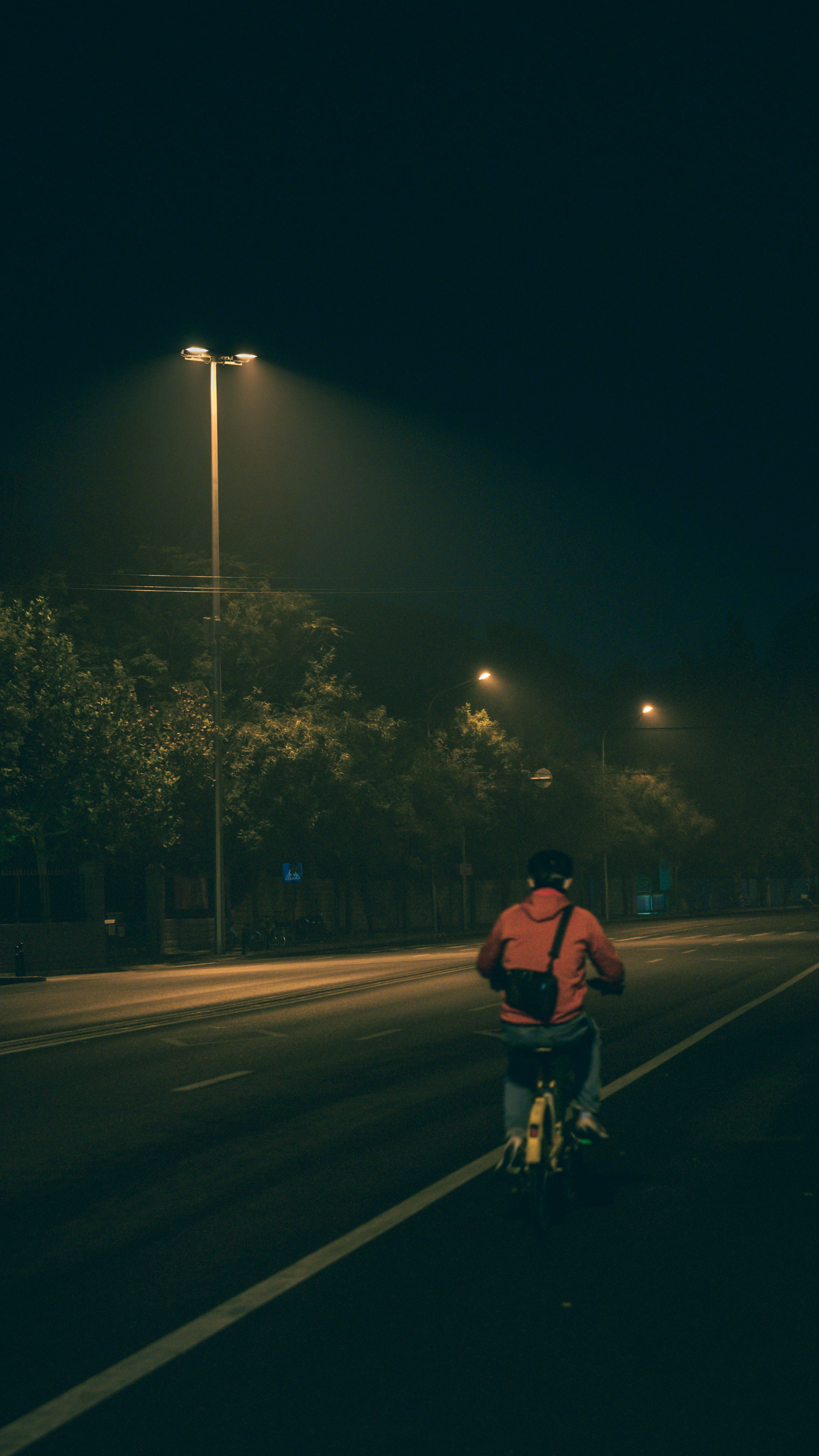 Haloed Night Ride: A Solitary Cyclist on a Quiet Street
