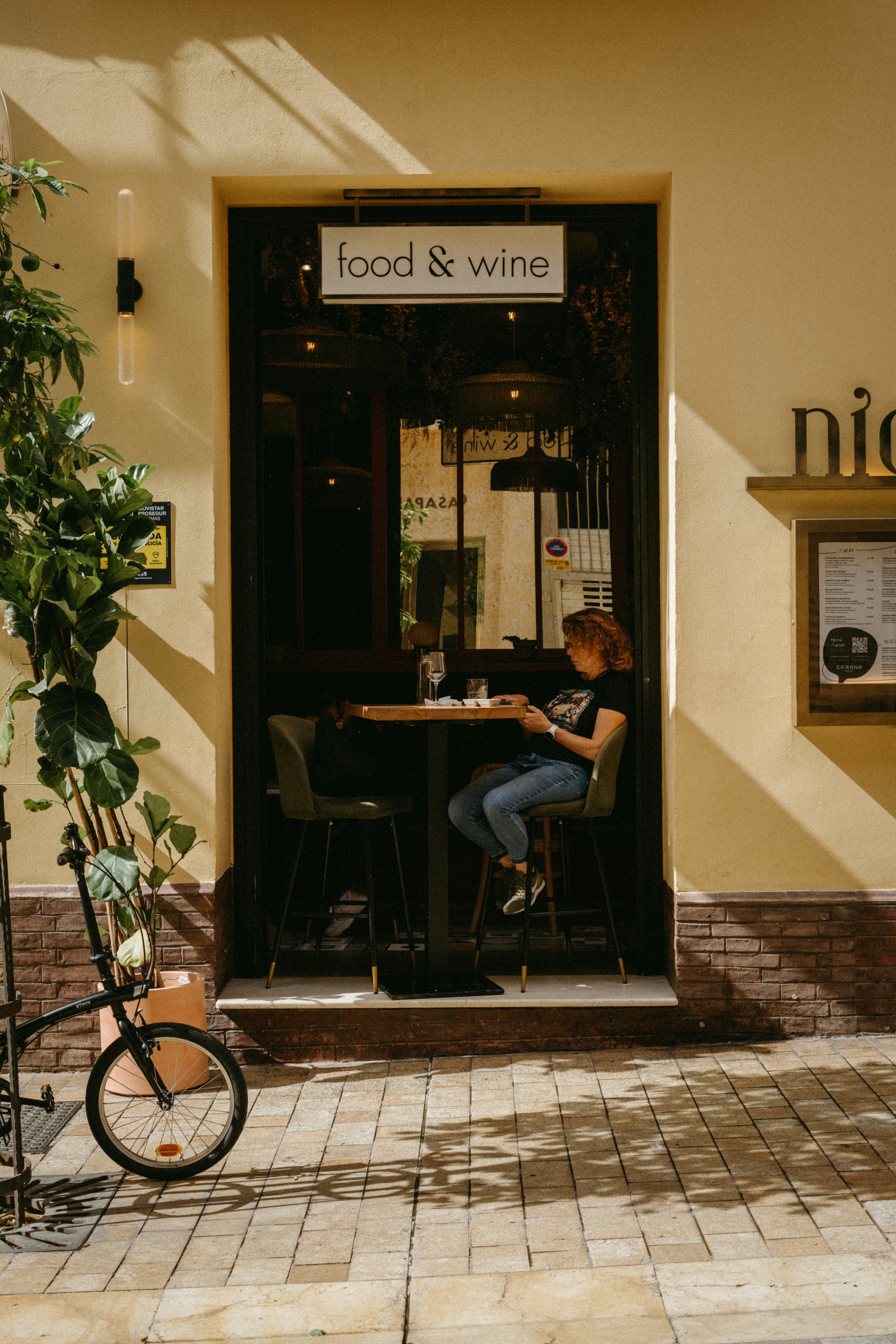 Sunlit doorway Bistro: a lone diner beneath the food & wine sign