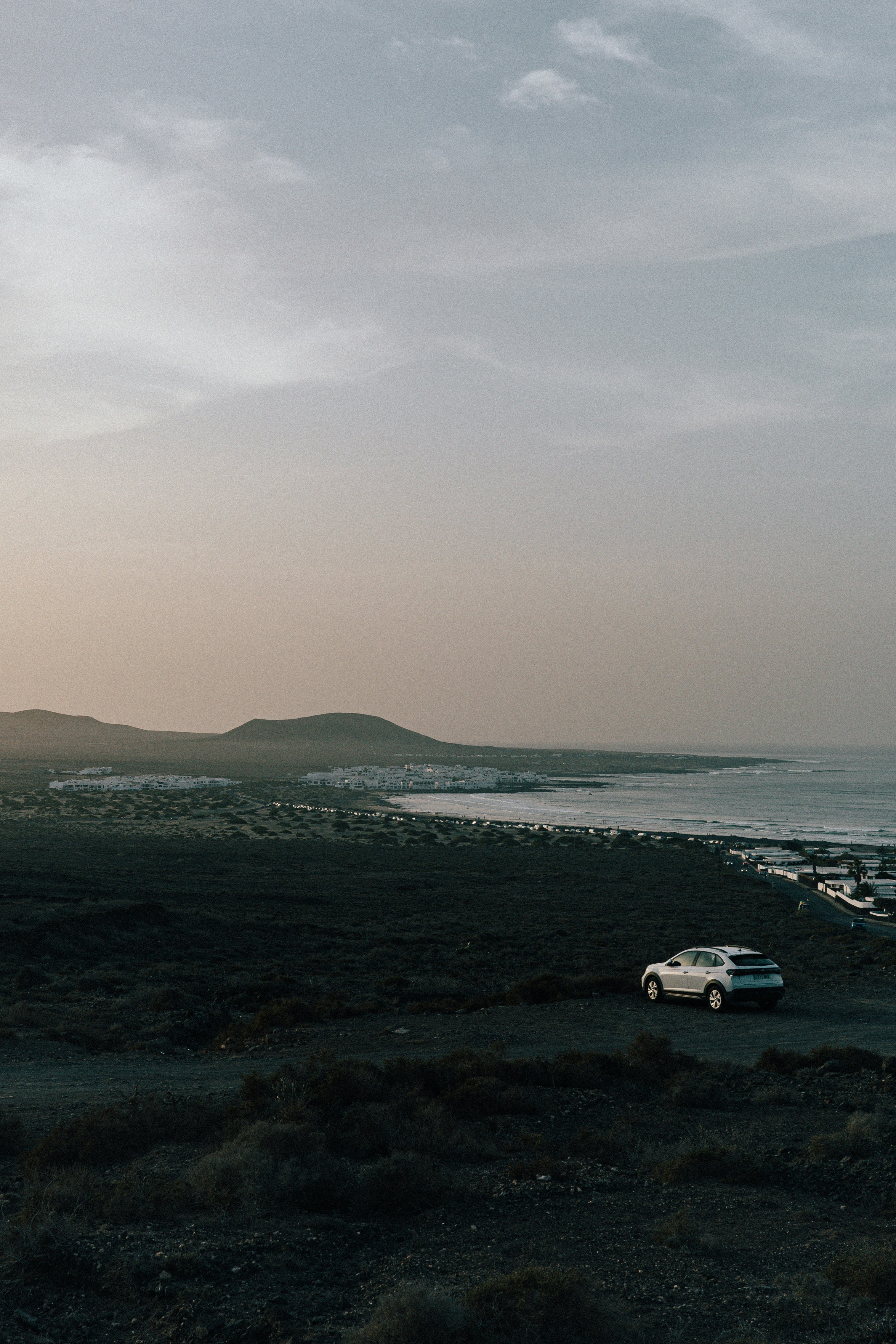 Lone SUV at Dusk Along a Volcanic Coast