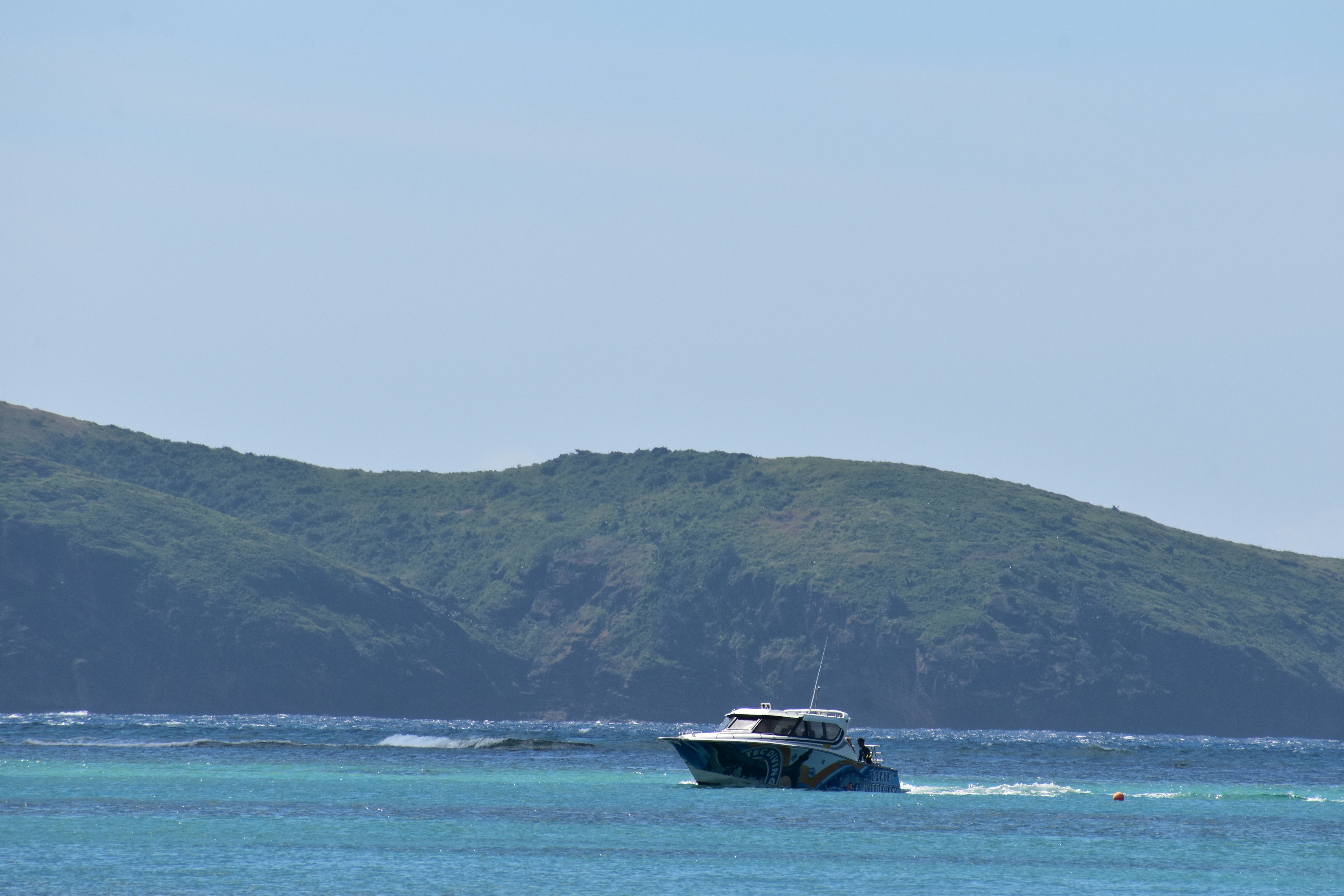 Turquoise Seascape: A Motorboat Quietly Traverses a Verdant Coastline