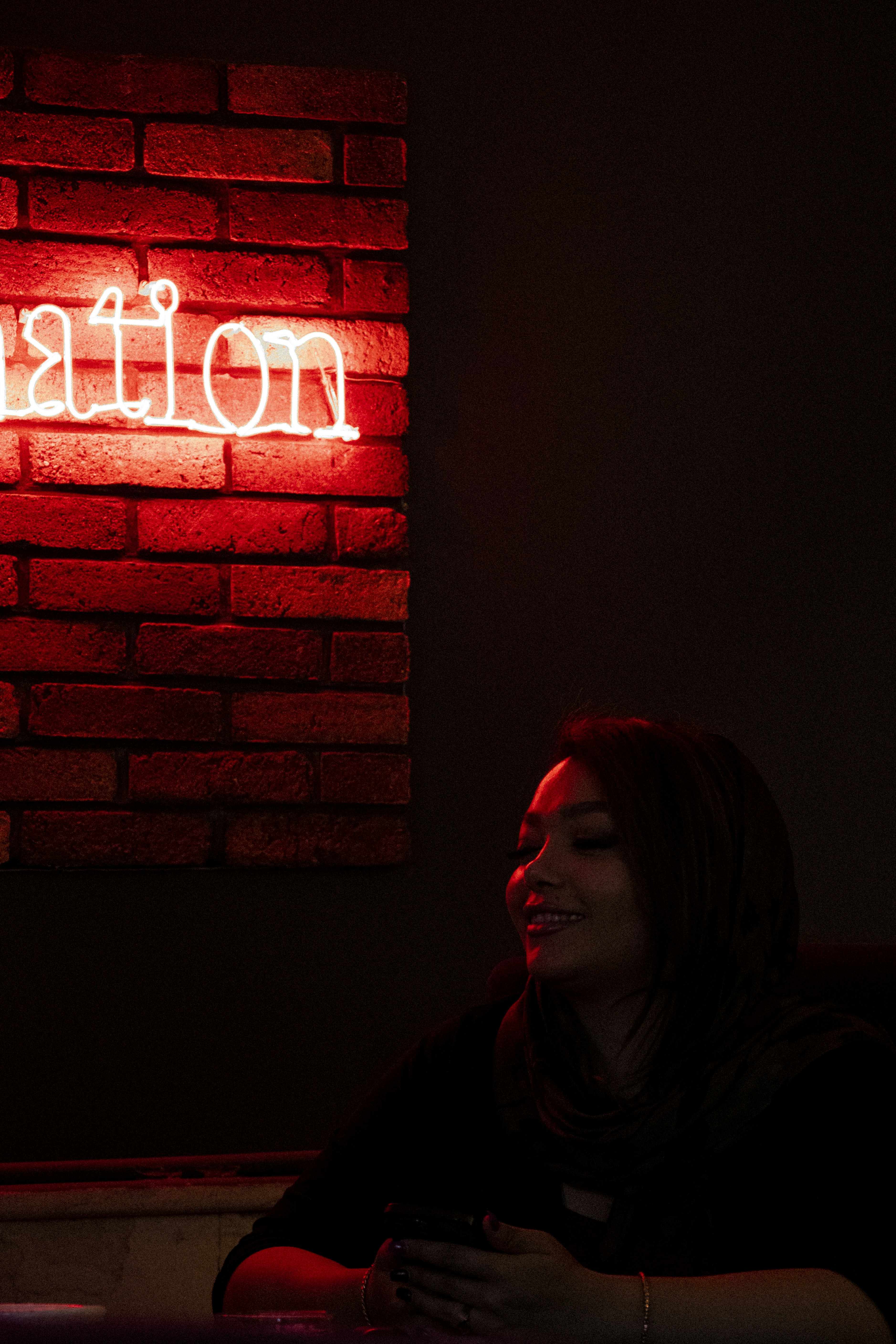A woman sitting at a table in front of a brick wall photo – Free ...
