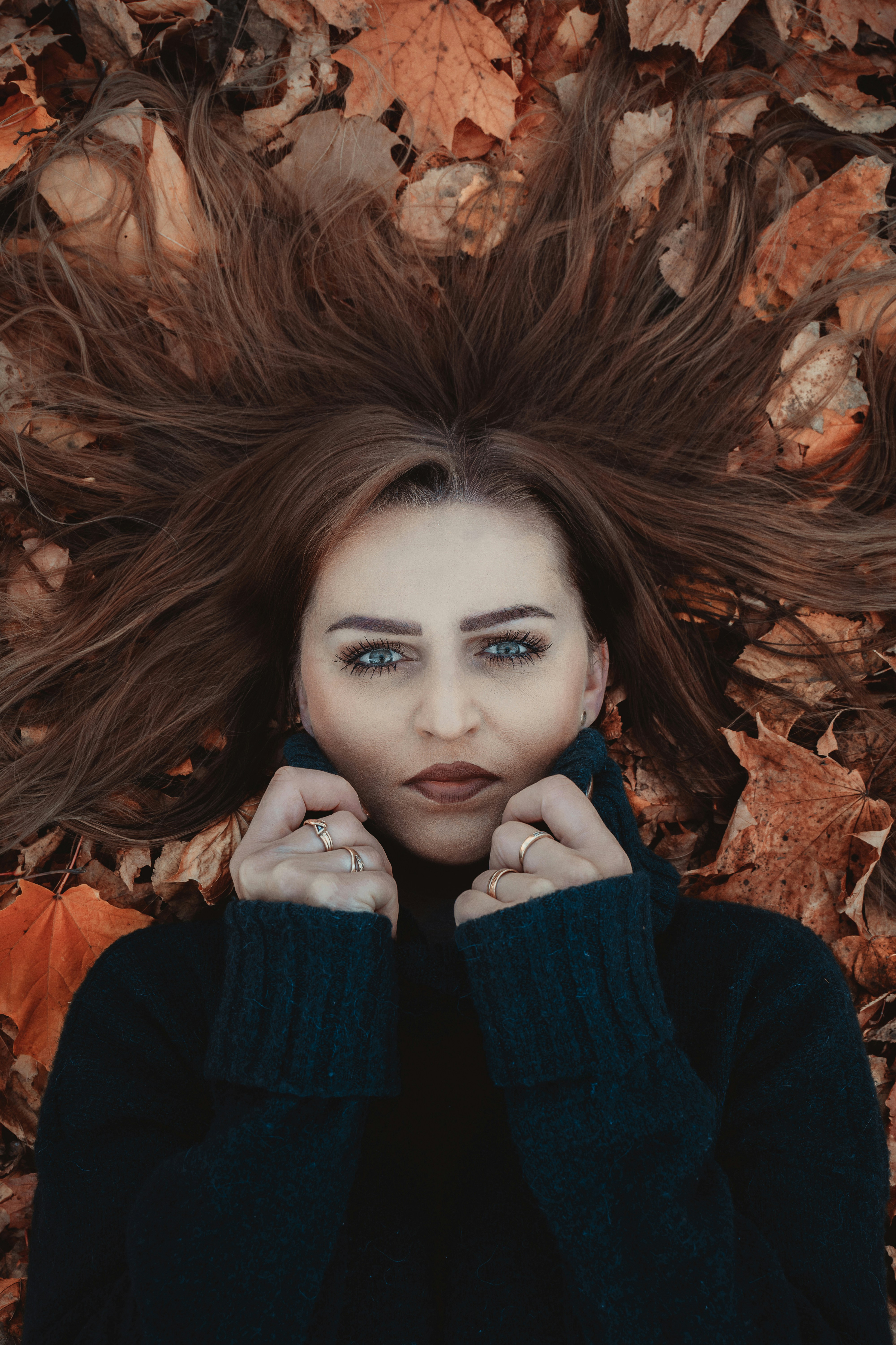 A woman laying in leaves with her hair blowing in the wind photo – Free ...