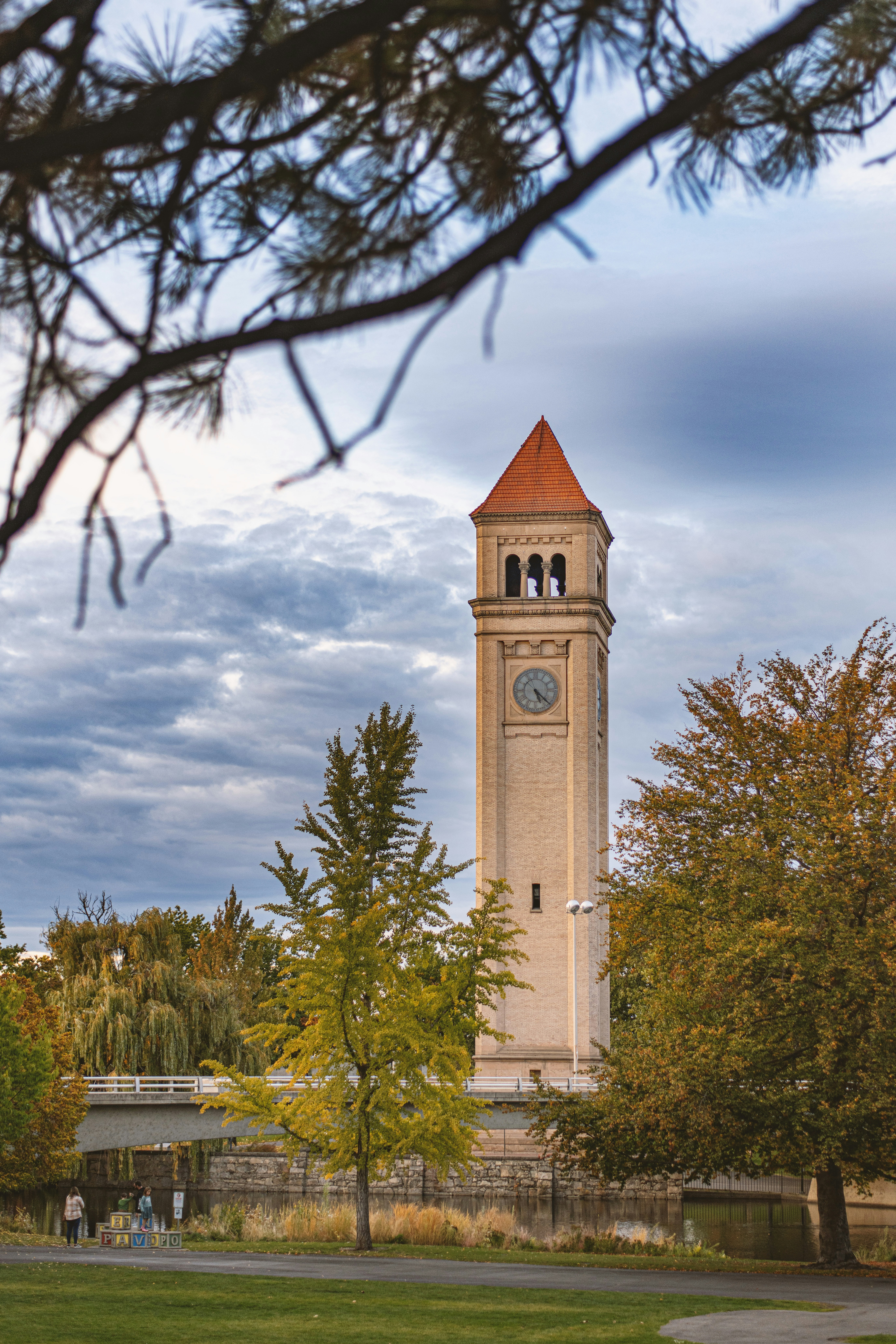 Autumn Clock Tower Rising Over the Riverside, Framed by Branches
