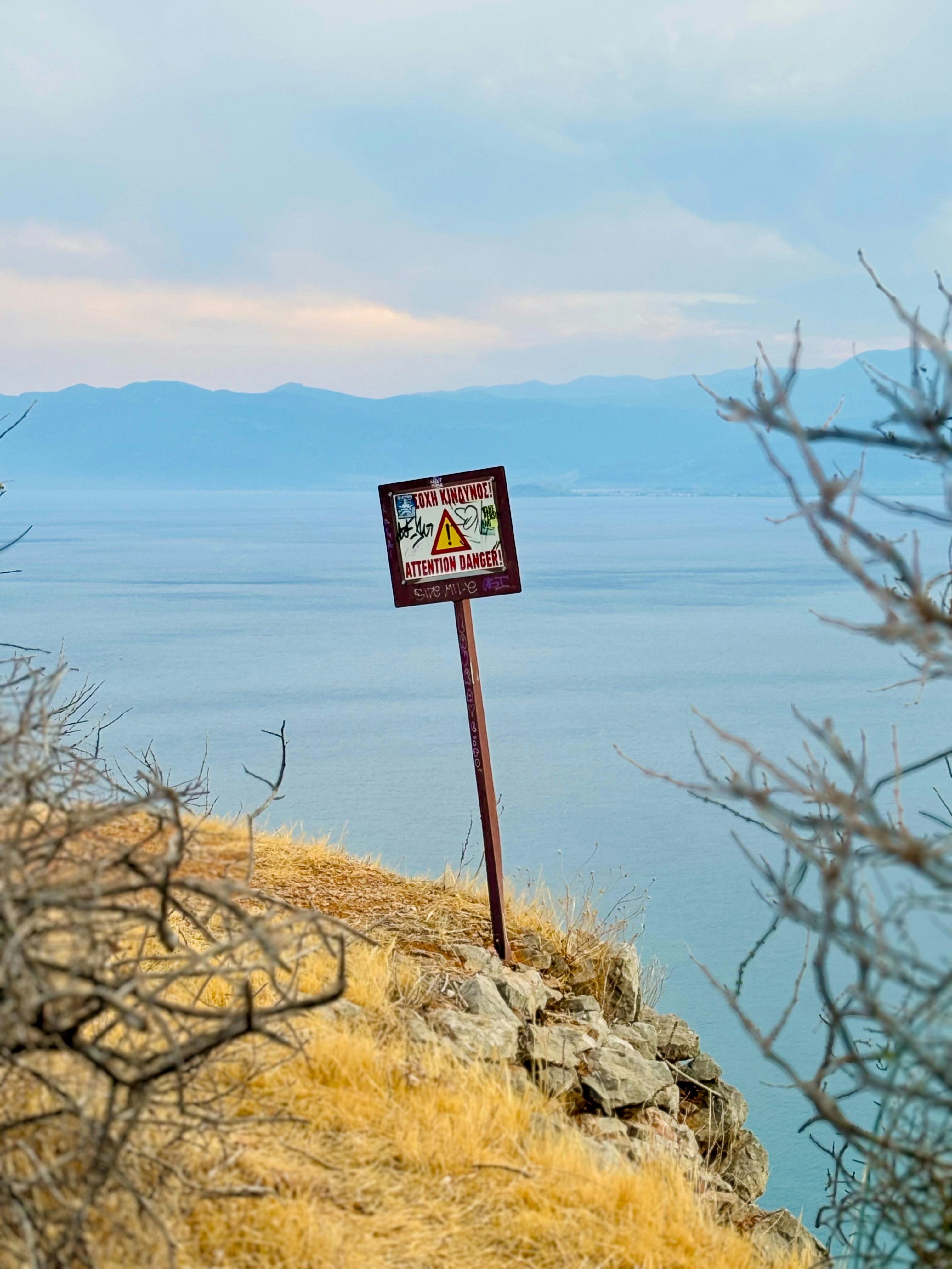 A sign on the side of a hill near the ocean