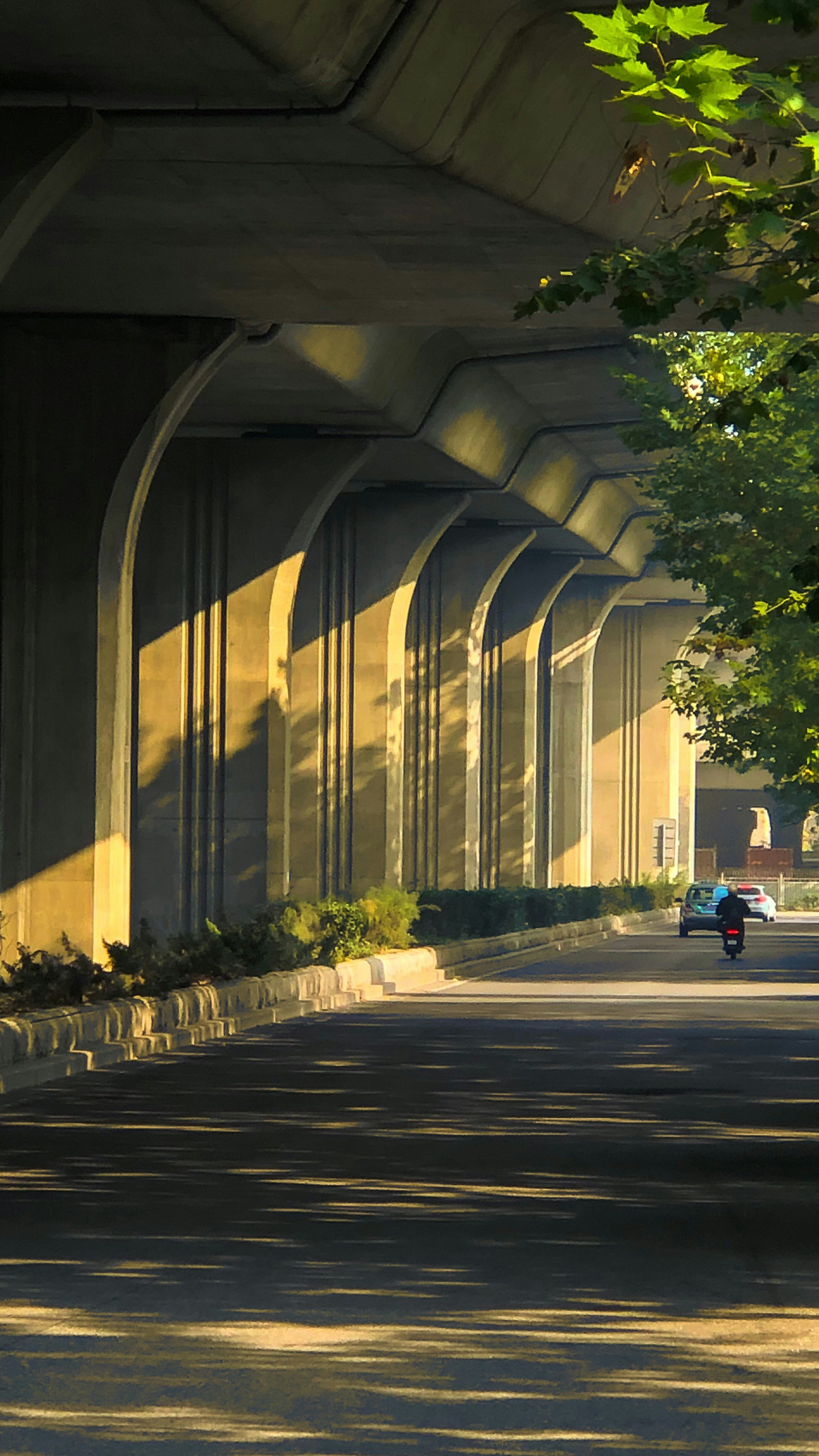 Morning lights shining under the bridge | A car driving down a street under a bridge