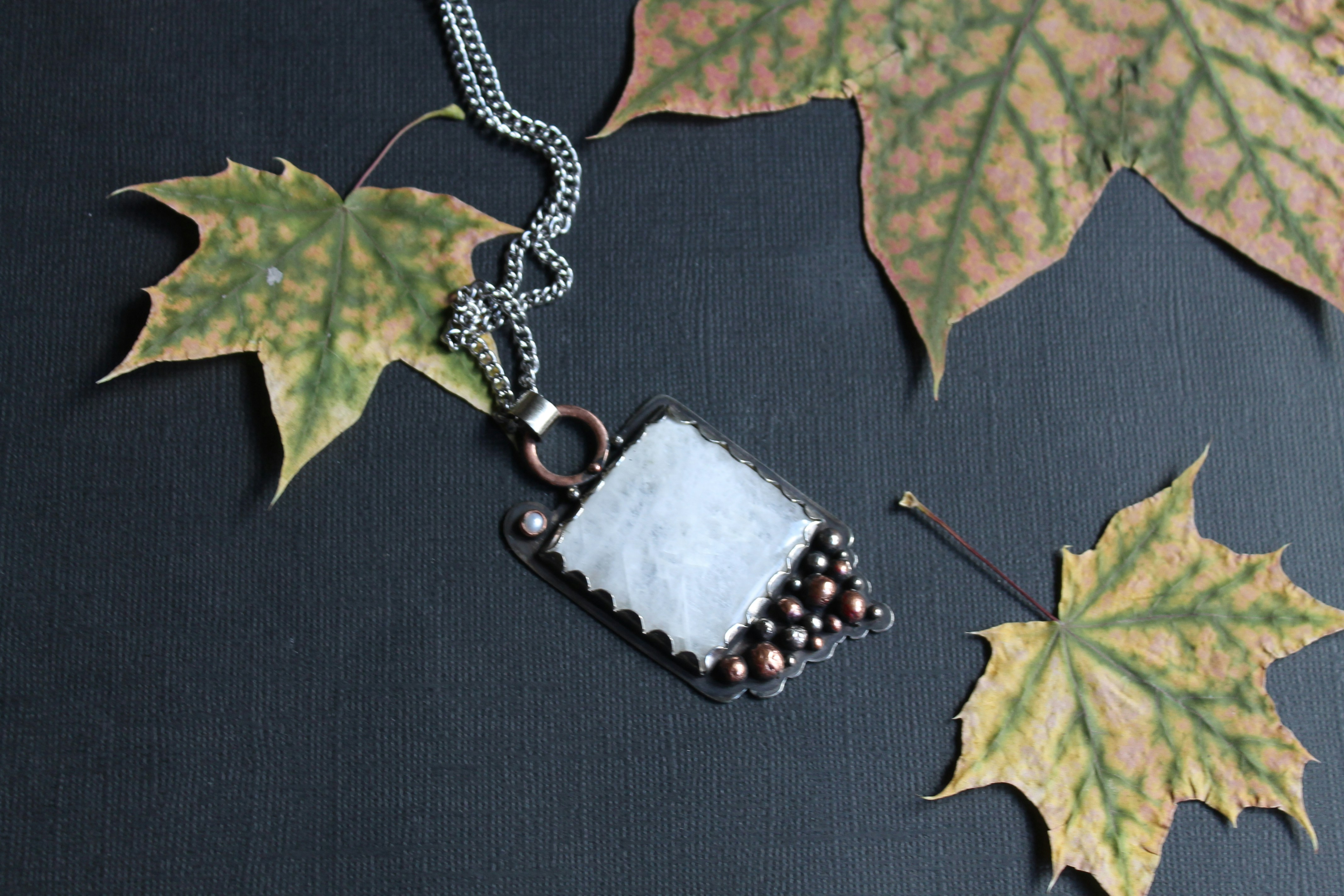 Pendant on dark canvas: an icy centerpiece framed by autumn leaves