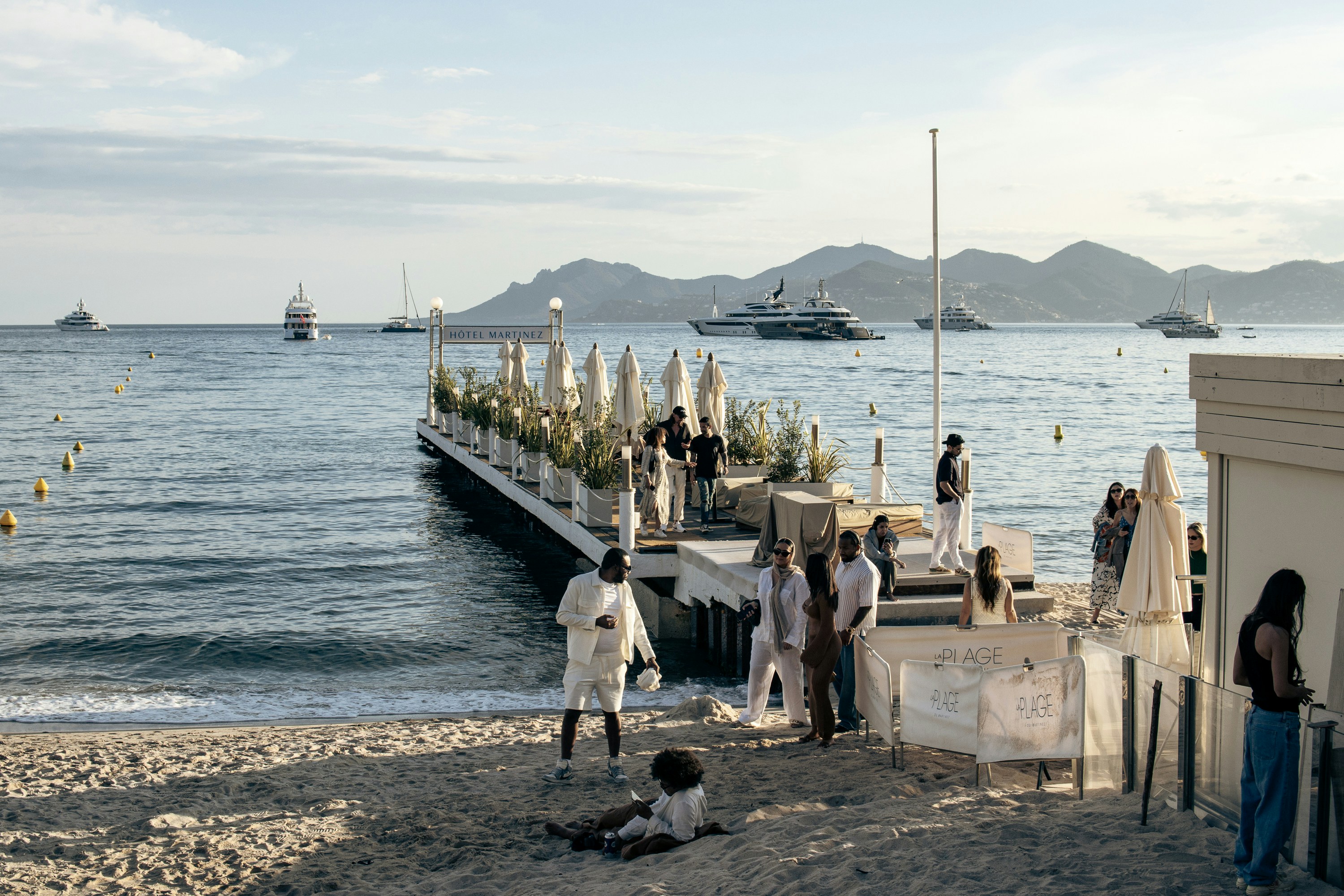 Passengers by the Pier: Evening Social on a Mediterranean Beachfront