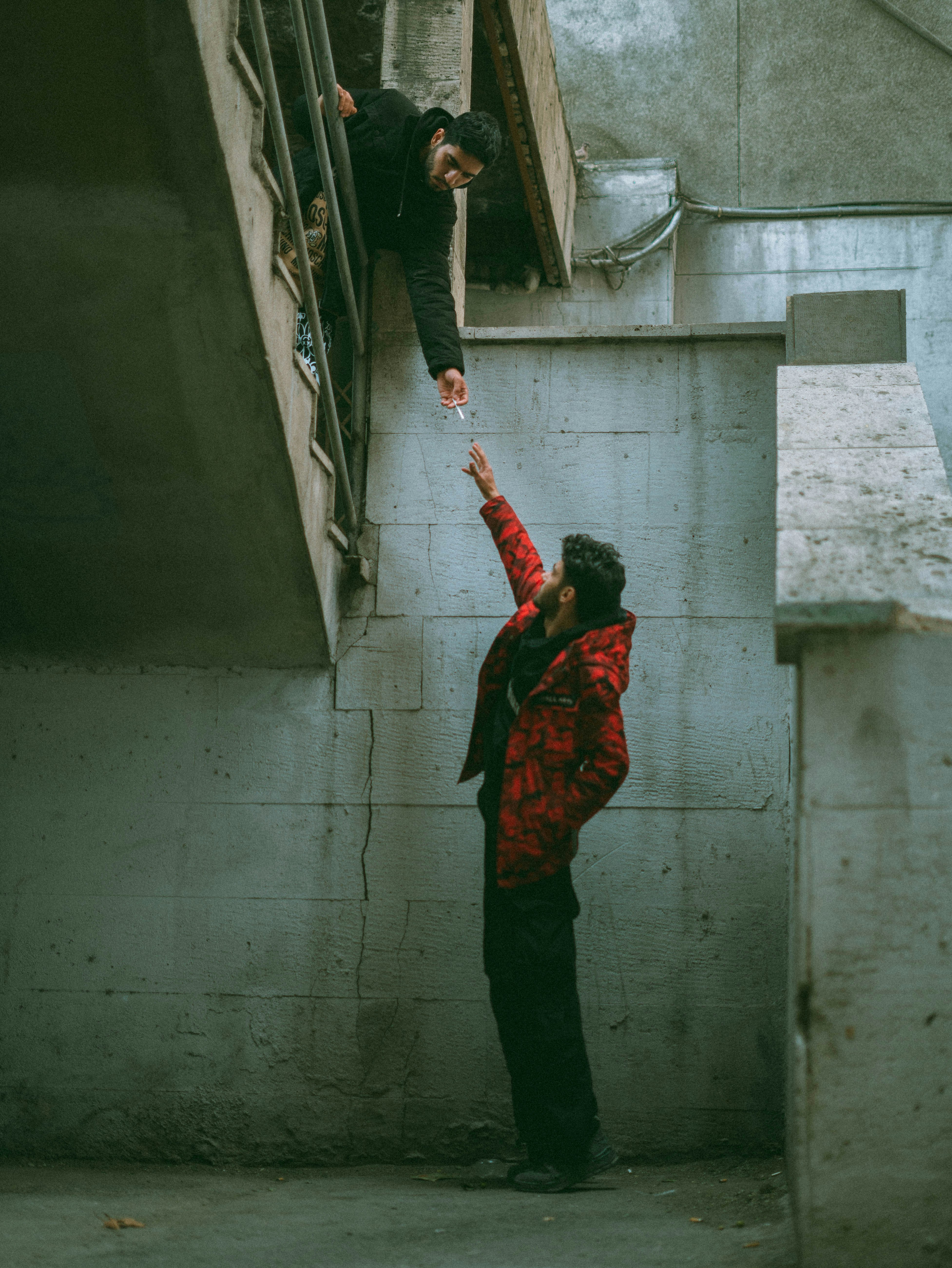 A man in a red jacket reaching up into a stairwell photo – Free Tehran ...