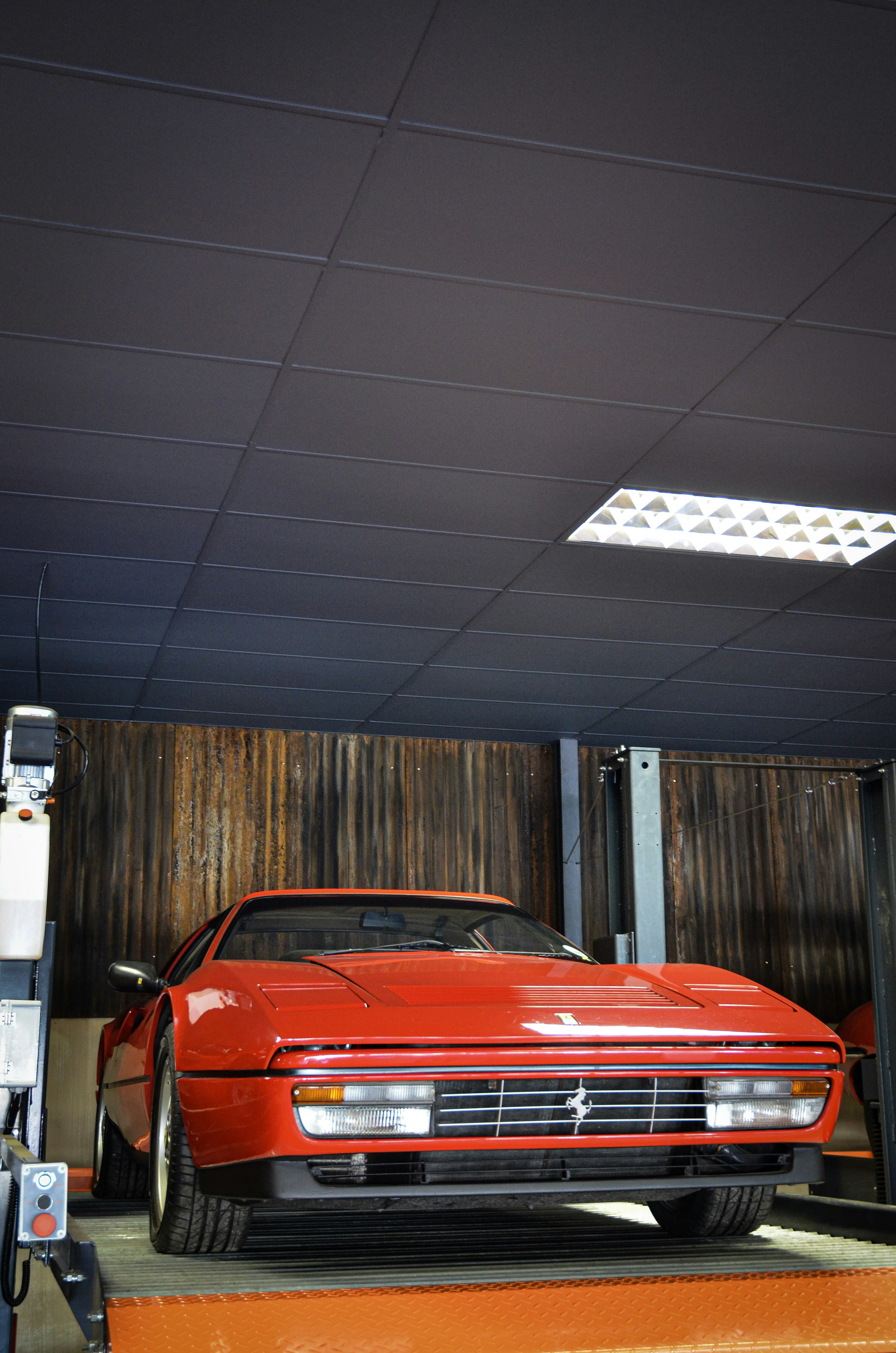Red Ferrari Emerges from the Industrial Garage on a Test Lift
