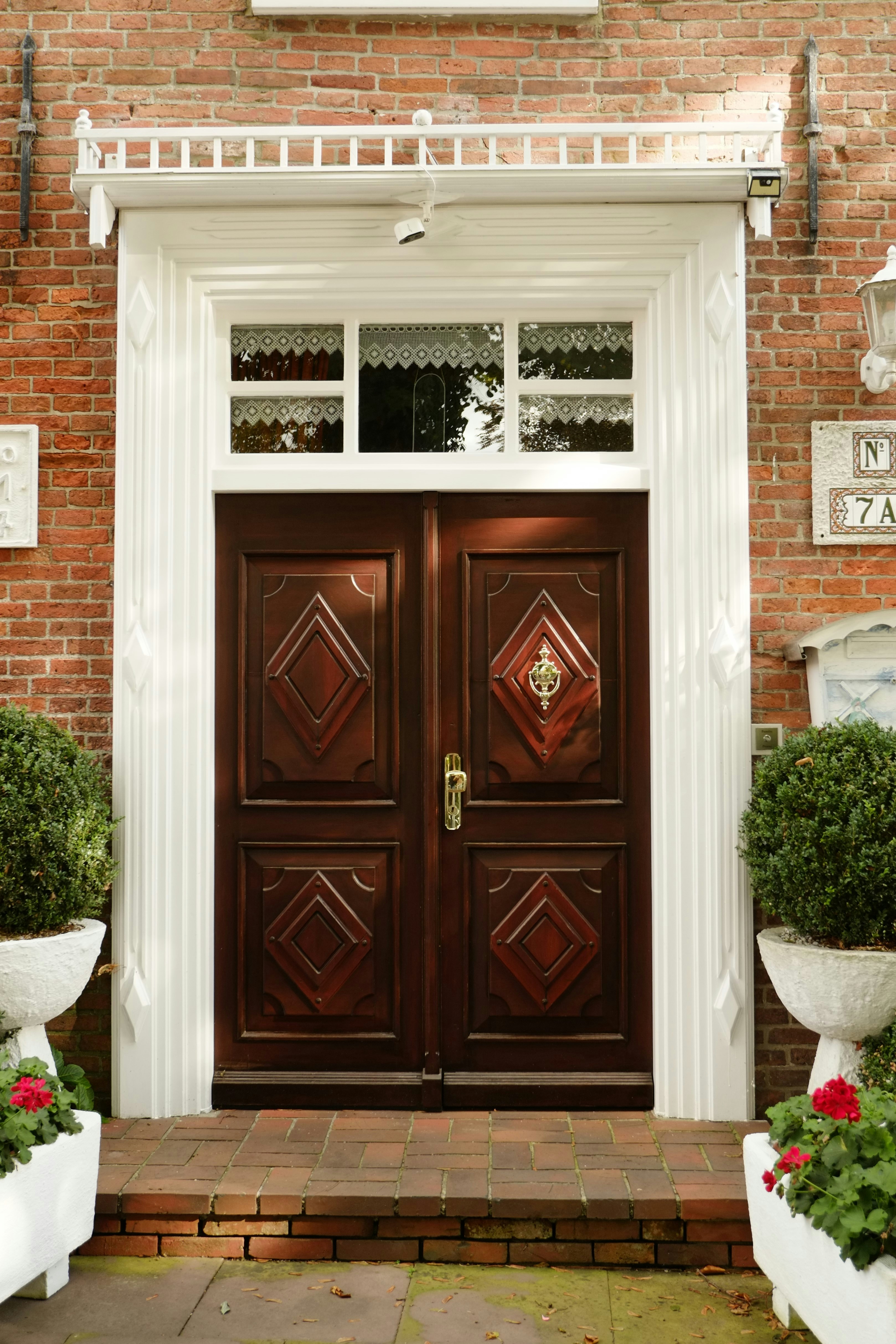 Diamond-Panel Doors Framed by White Trim on a Brick Townhouse