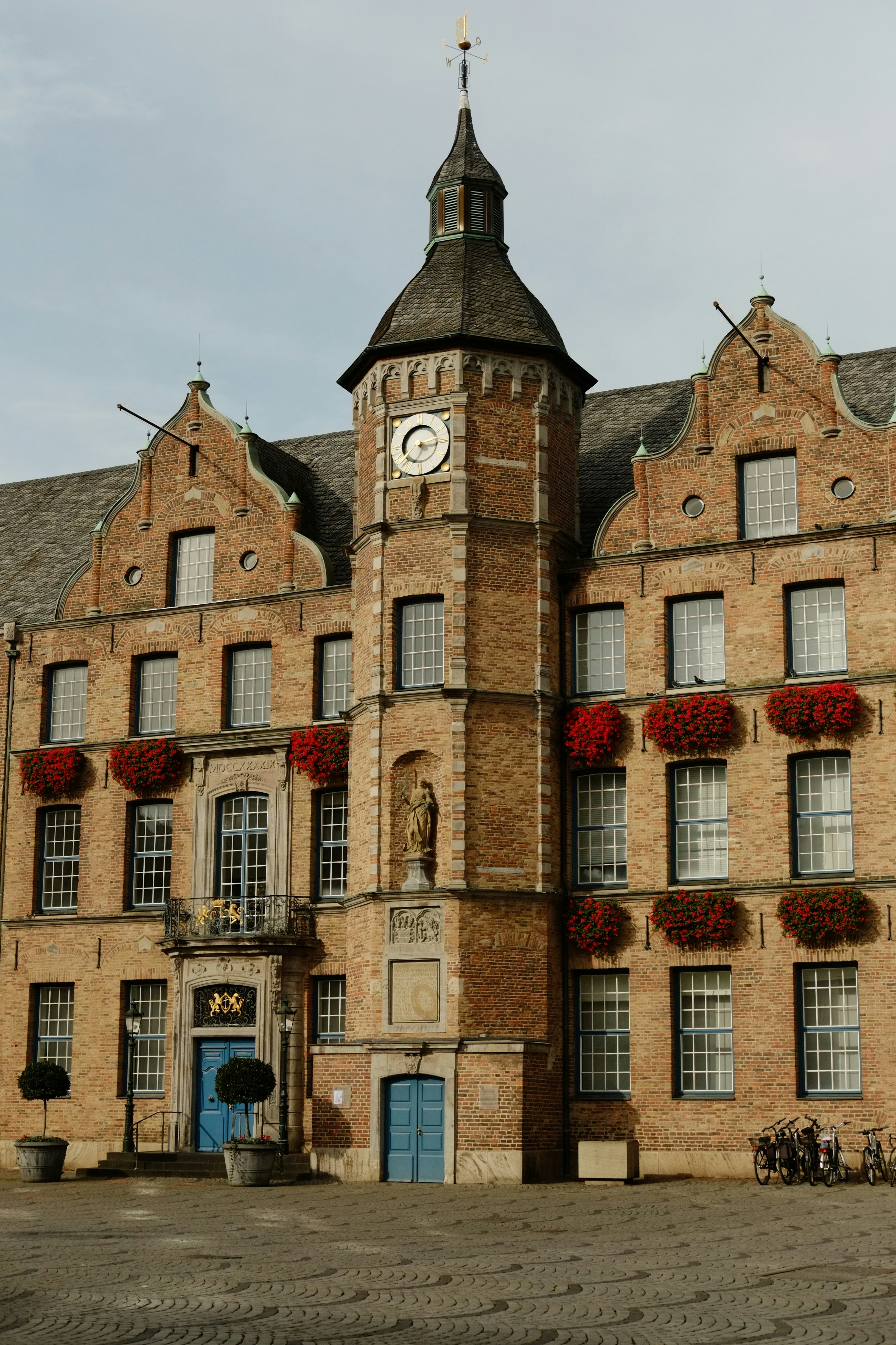 Clocktower Courtyard: Red Bouquets Framing a Brick Town Hall Facade
