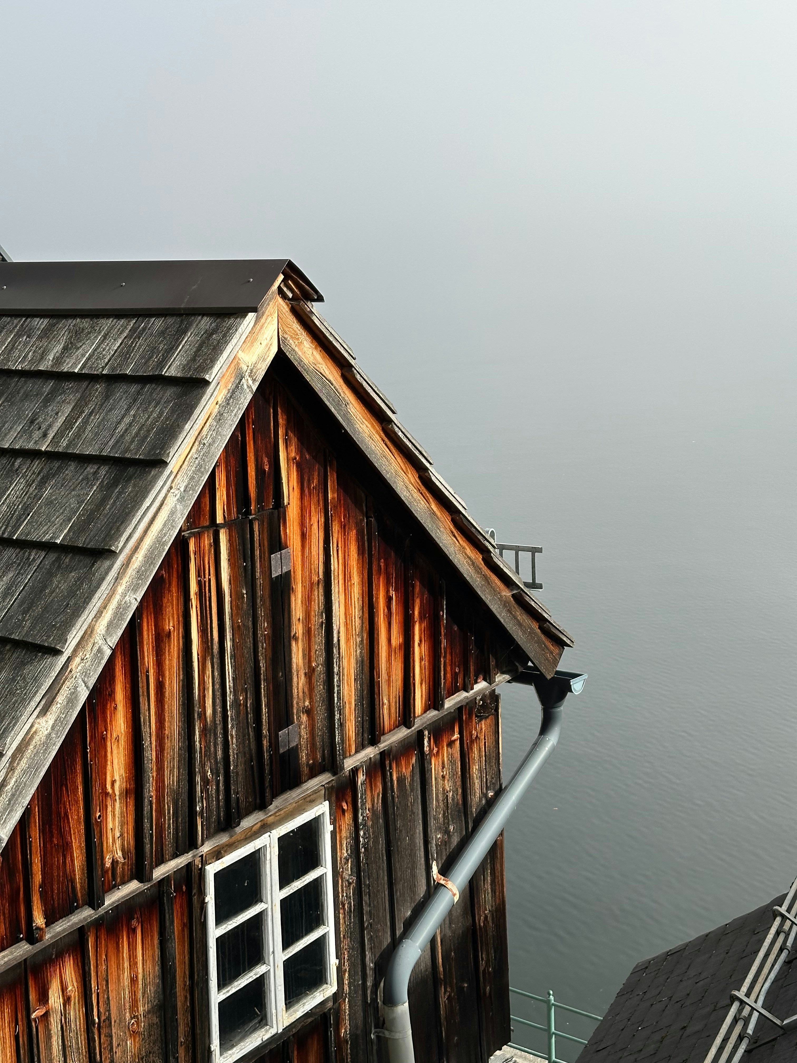 Gabled Timber Facade Leaning Toward a Misty Waterfront