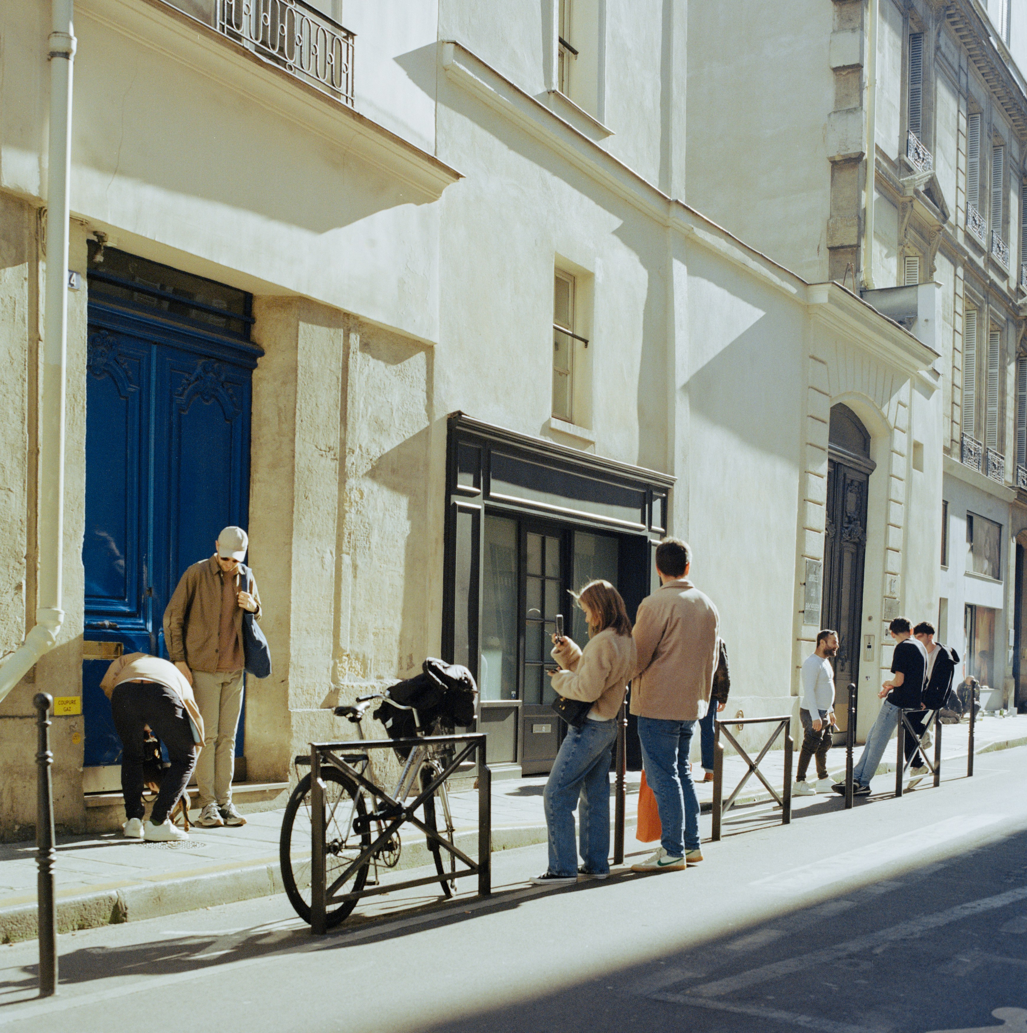 A group of people standing on the side of a street photo – Free Analog ...