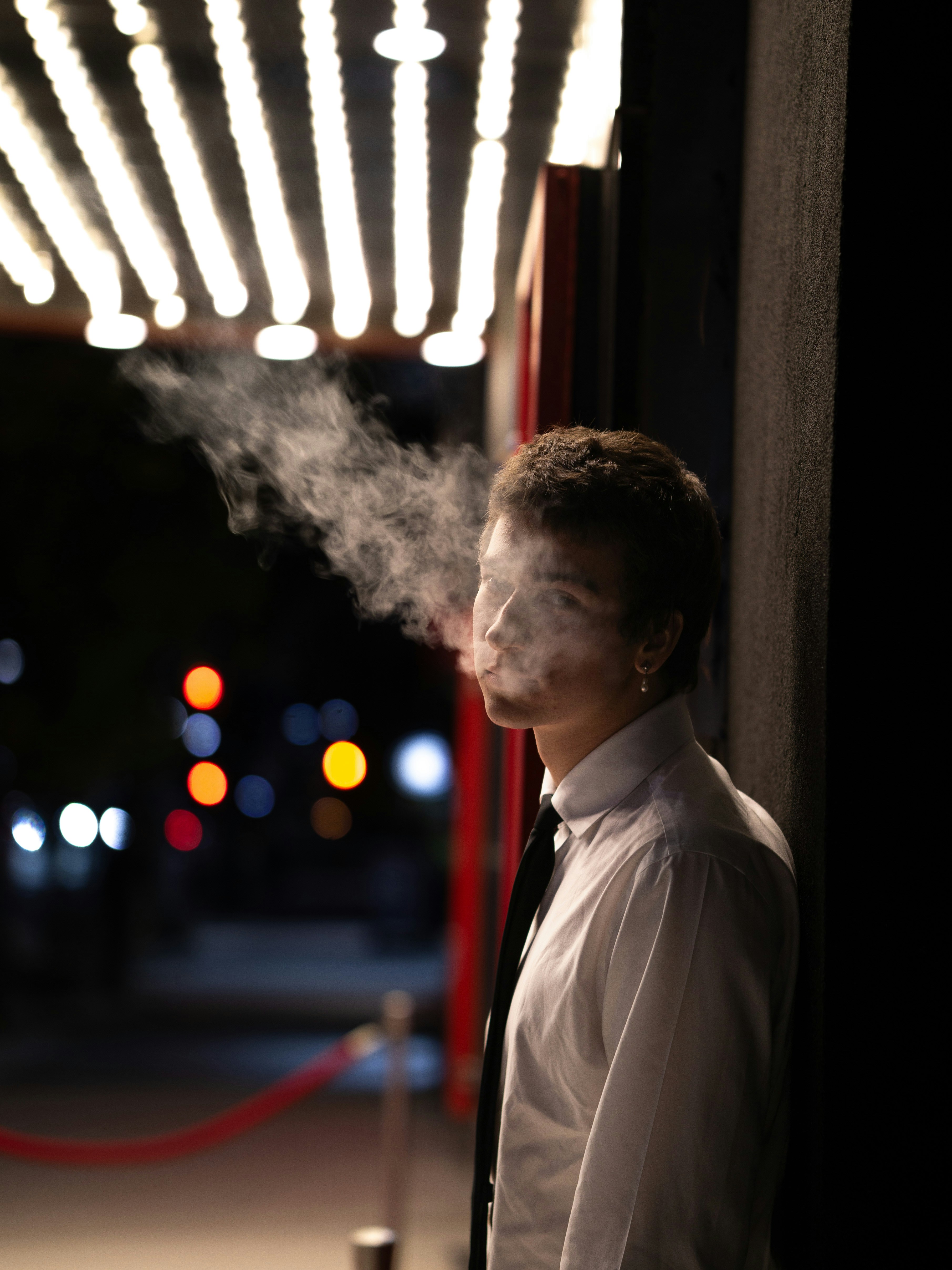 A man standing outside of a building smoking a cigarette photo – Free ...