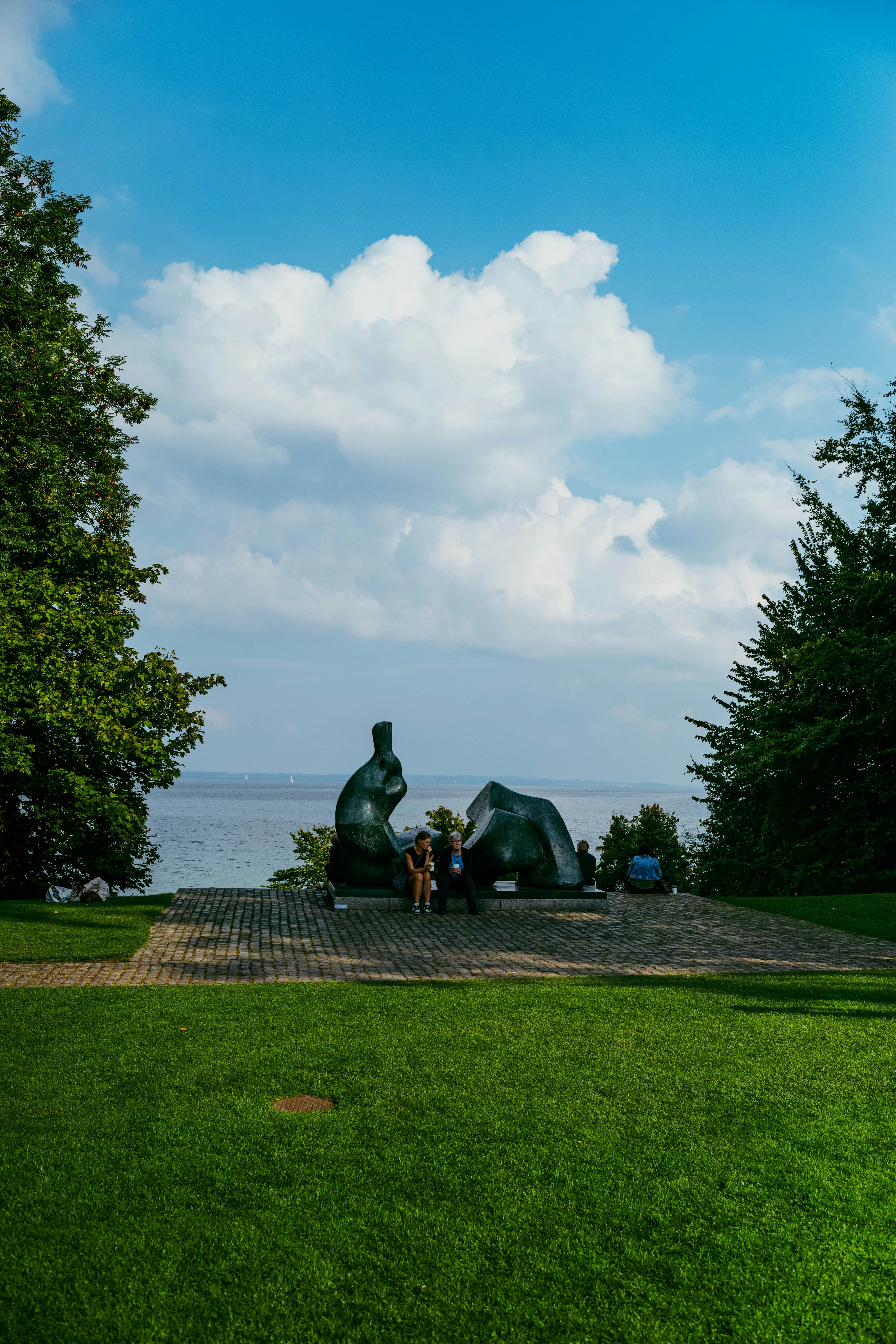 A couple of statues sitting on top of a lush green field photo – Free ...
