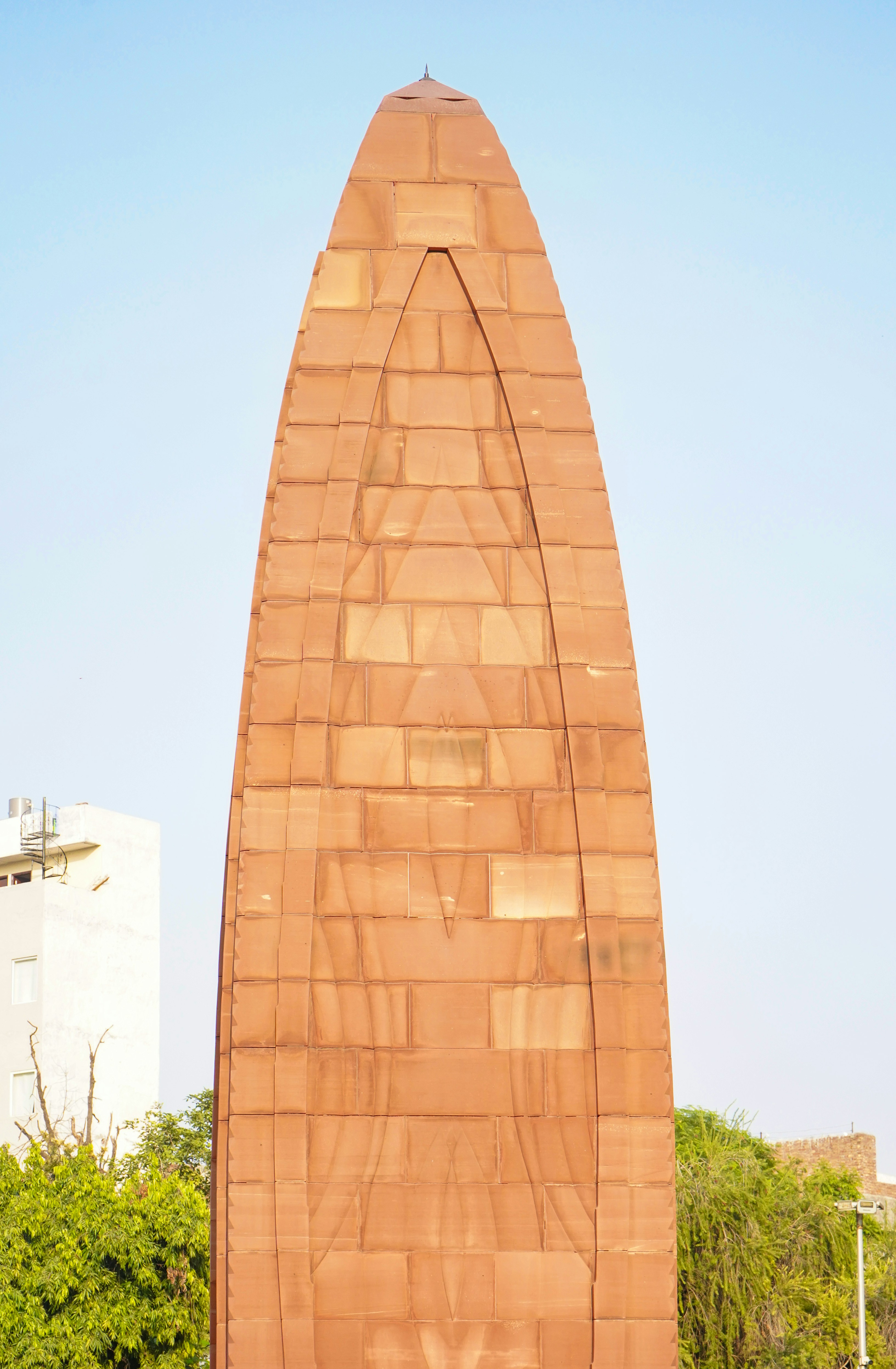 Ember Obelisk Rising: a brick-clad monument against a clear blue sky