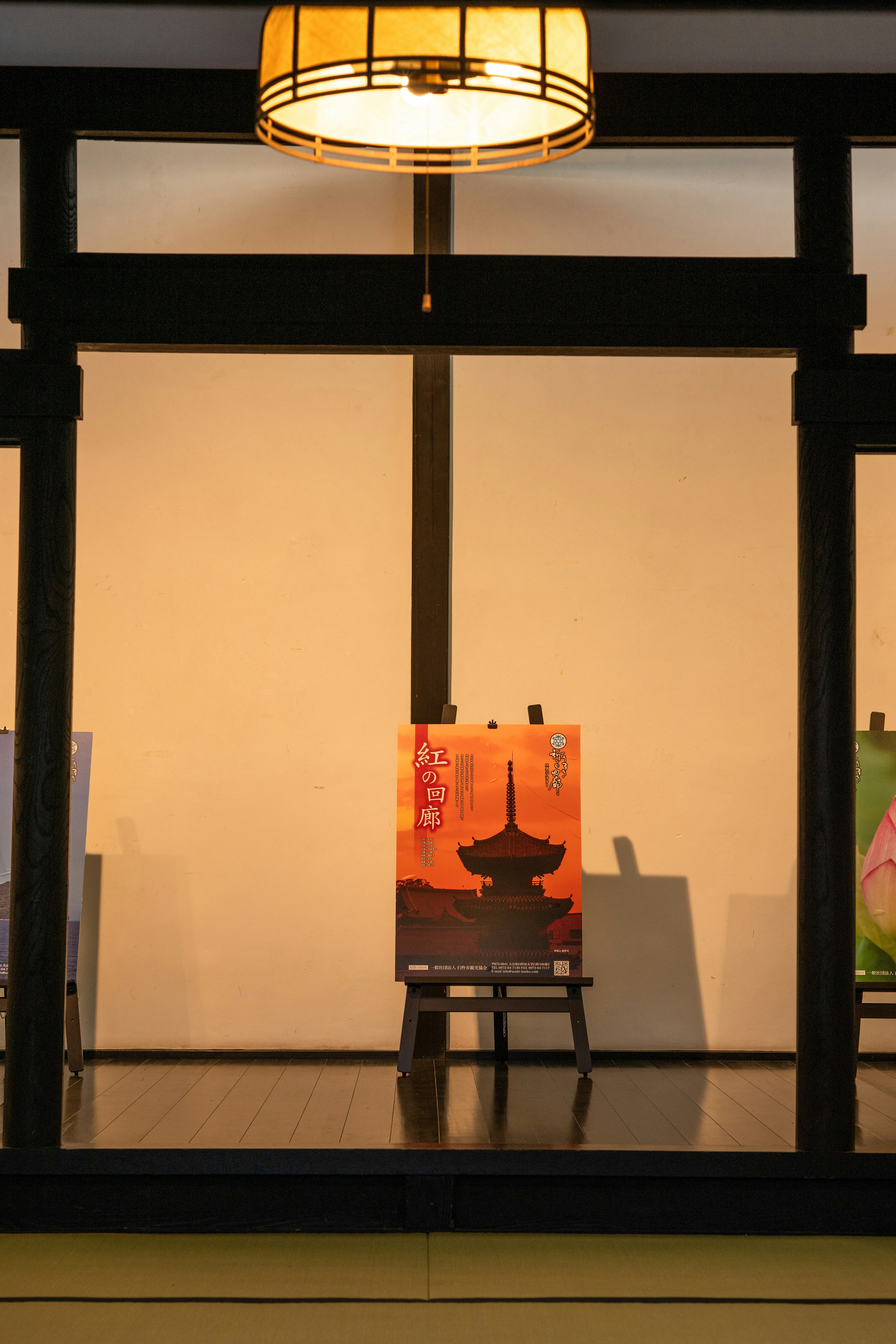Amber Lantern Framing a Red-Temple Poster in a Minimal Hall