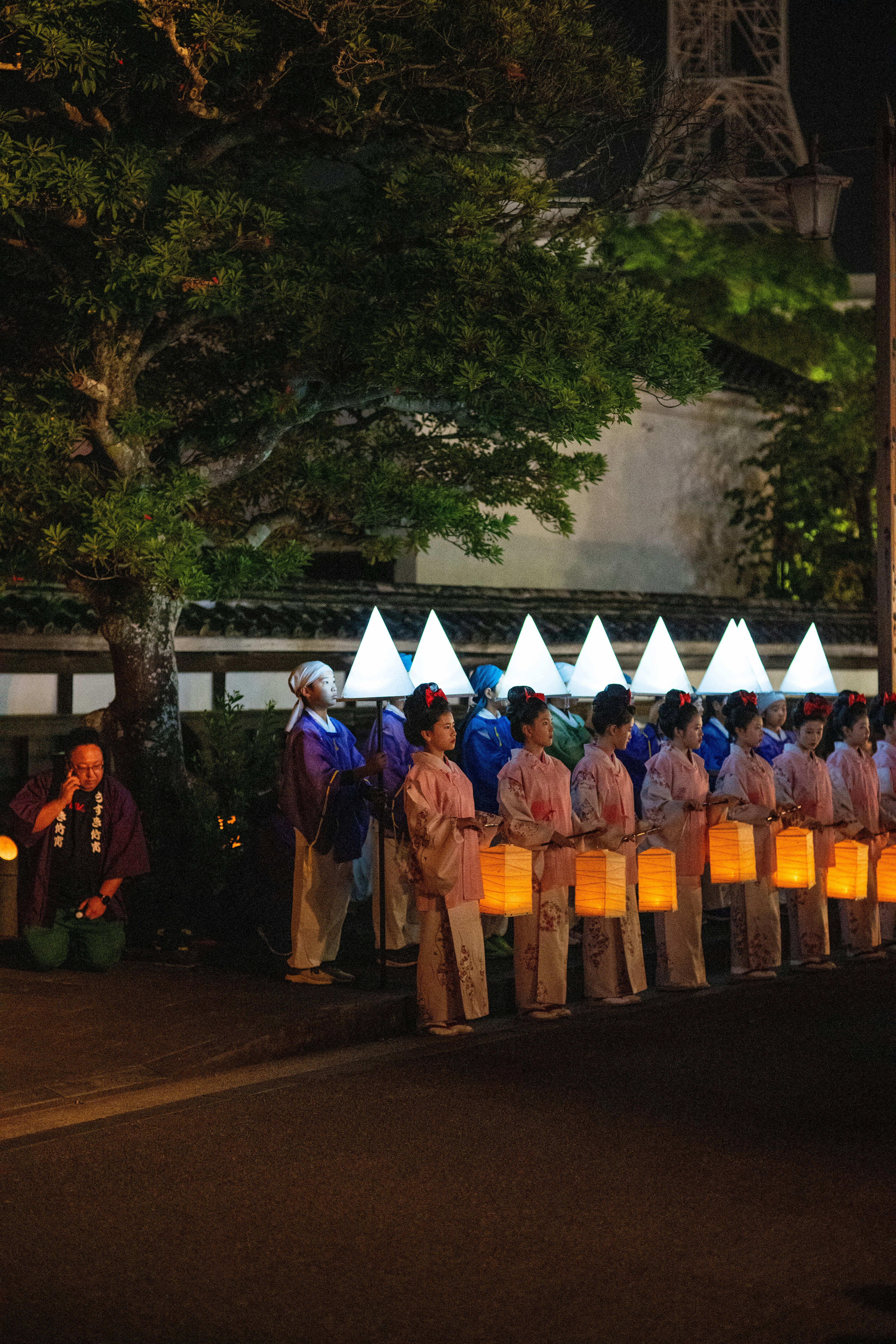 Night ceremony: lanterns illuminate a line of performers in traditional dress