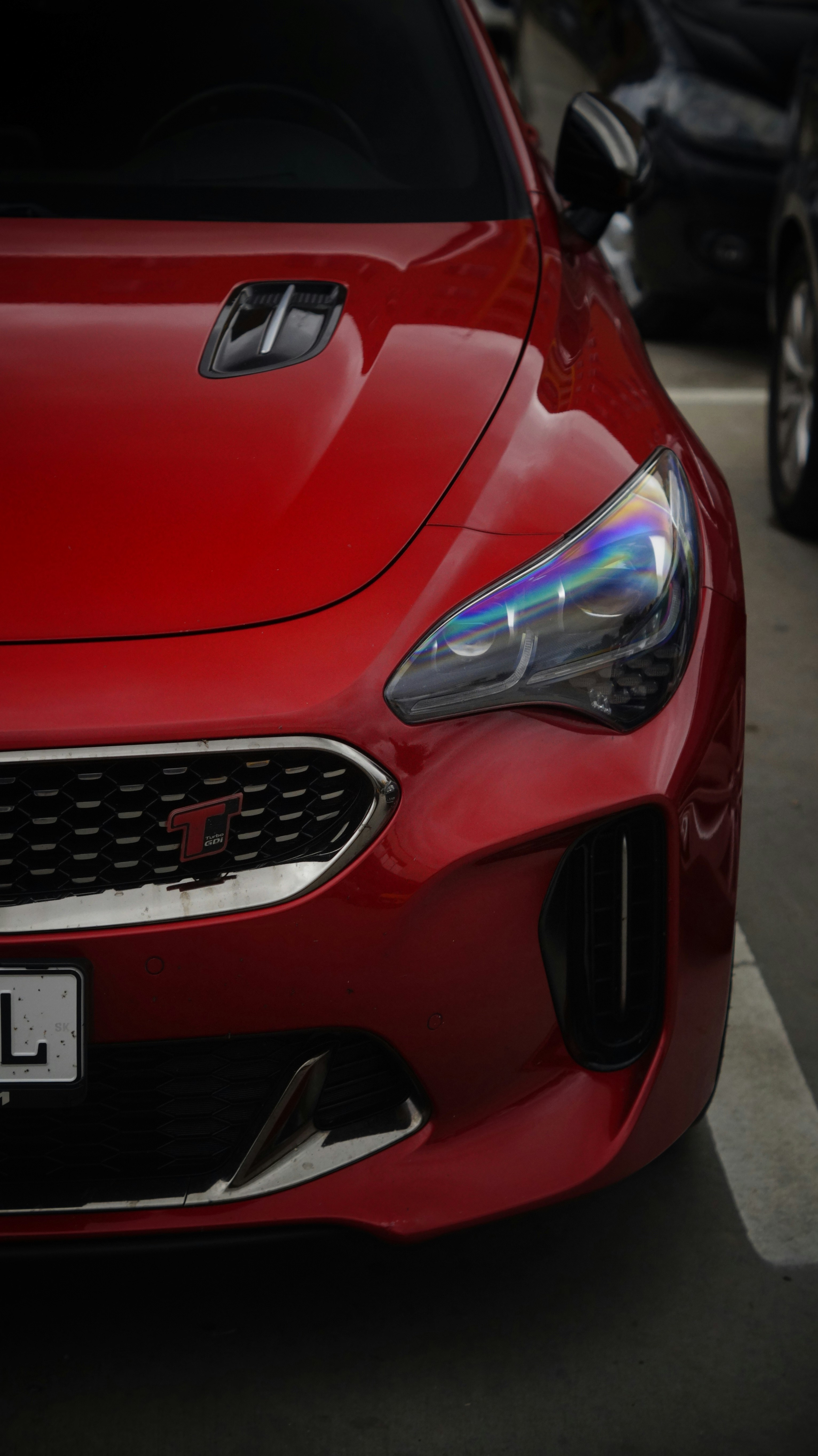 Close-up of a vibrant red sports car showcasing its sleek design and distinctive headlights. The aggressive front grille adds to its sporty appeal.