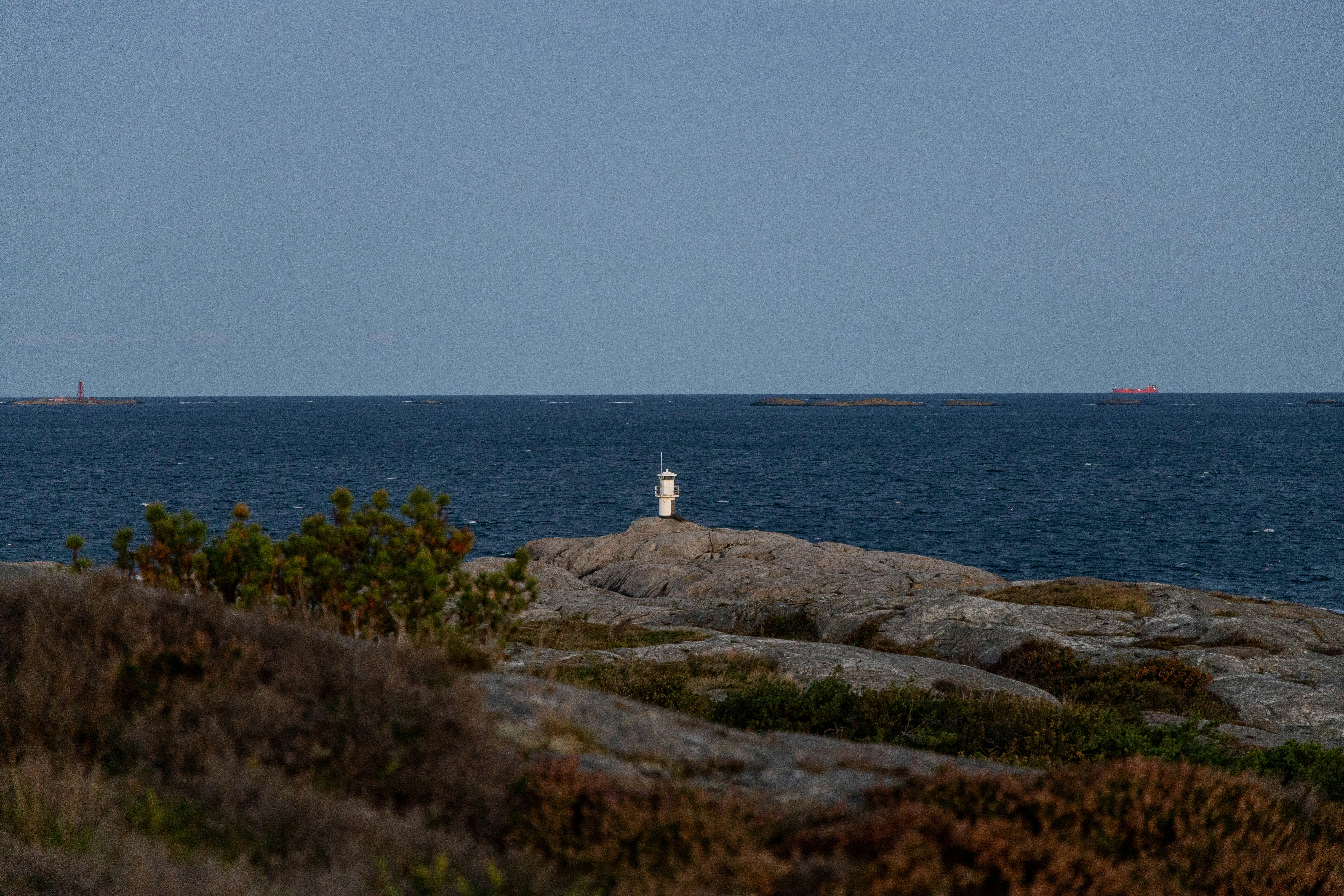 A lighthouse on a rocky outcropping near the ocean photo – Free ...