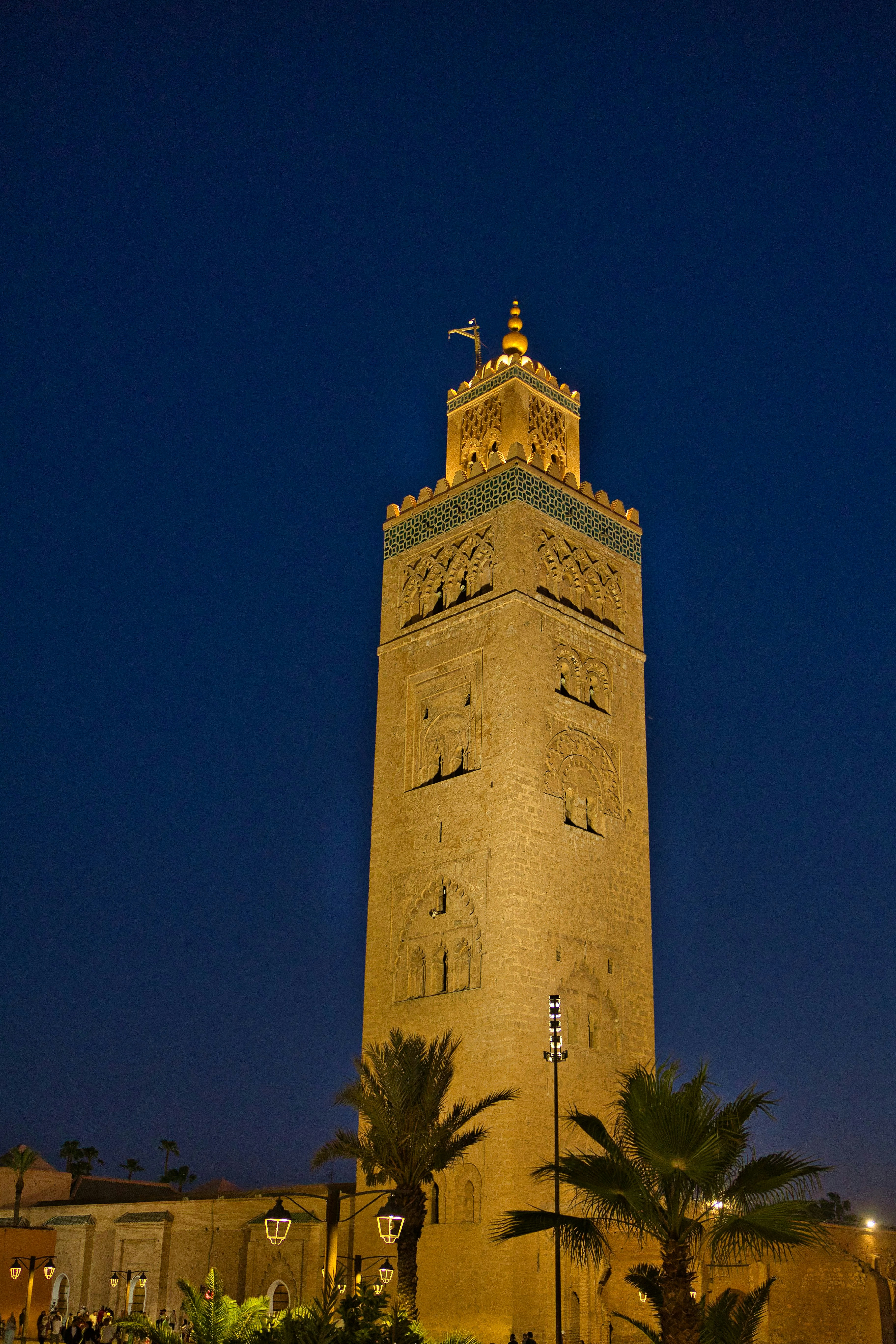 Nocturnal Beacon: The Golden Minaret Standing Over a Palm-Fringed Plaza