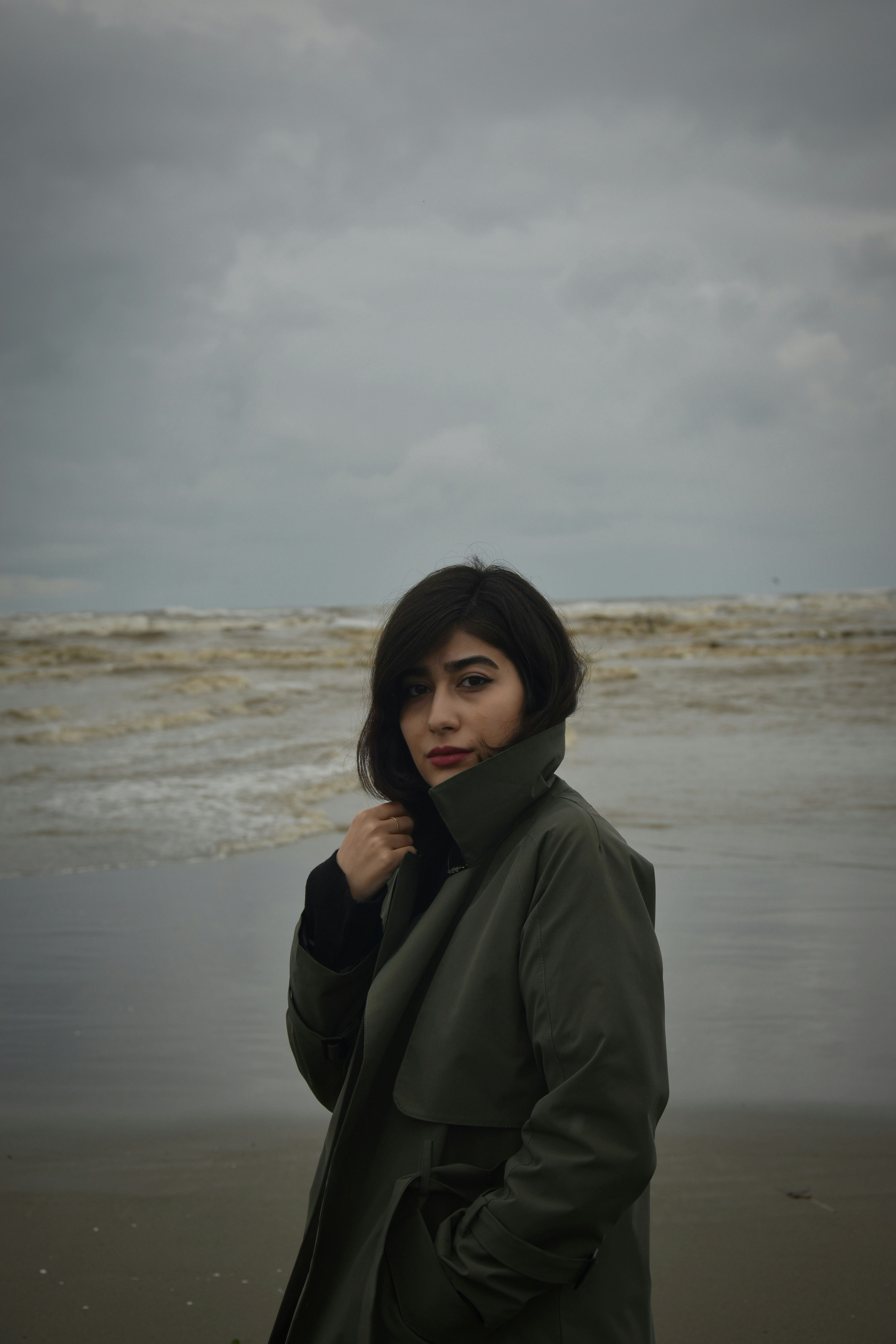 Olive Coat Portrait at the Quiet Shore Under a Clouded Sky